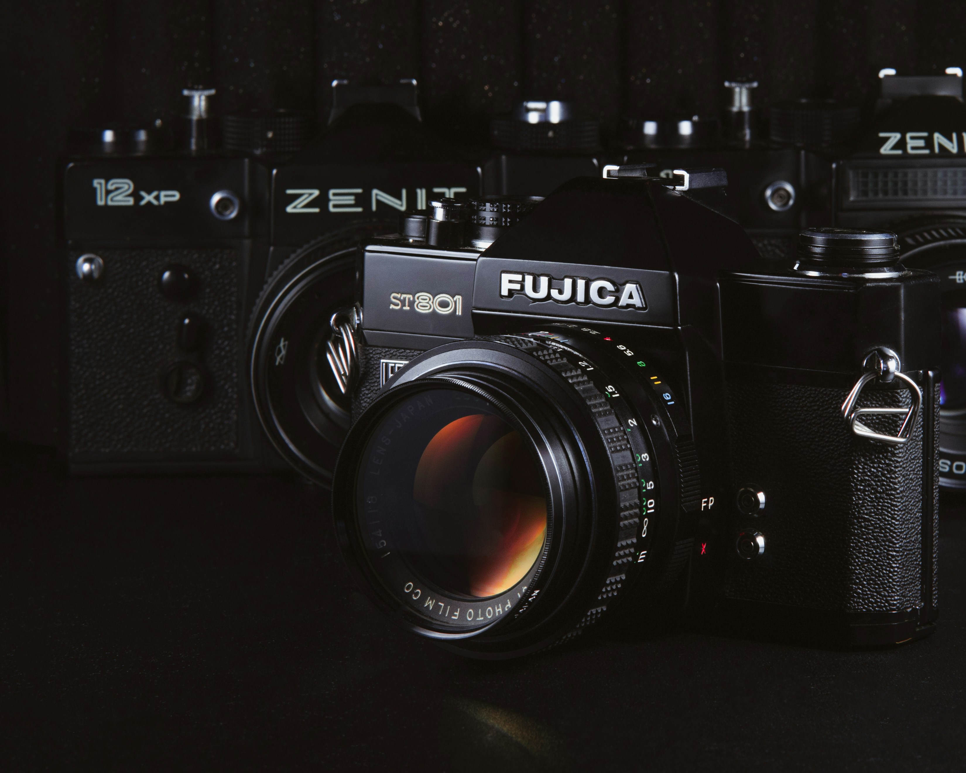 Fujica ST801 camera prominently displayed with a collection of Zenit cameras in the background, showcasing vintage photography gear.