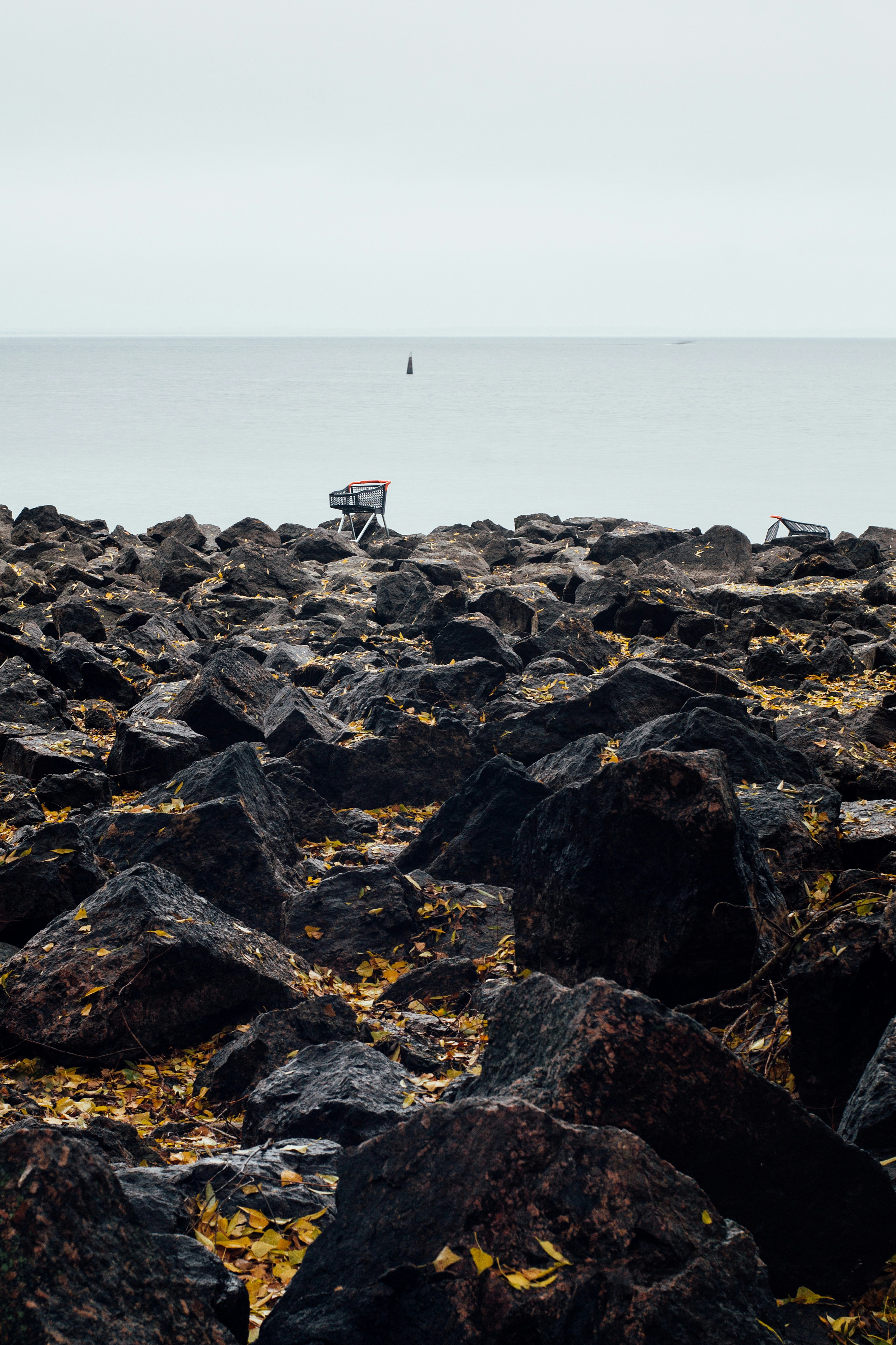 Rocky shoreline leading to a calm, overcast sea under a muted sky.