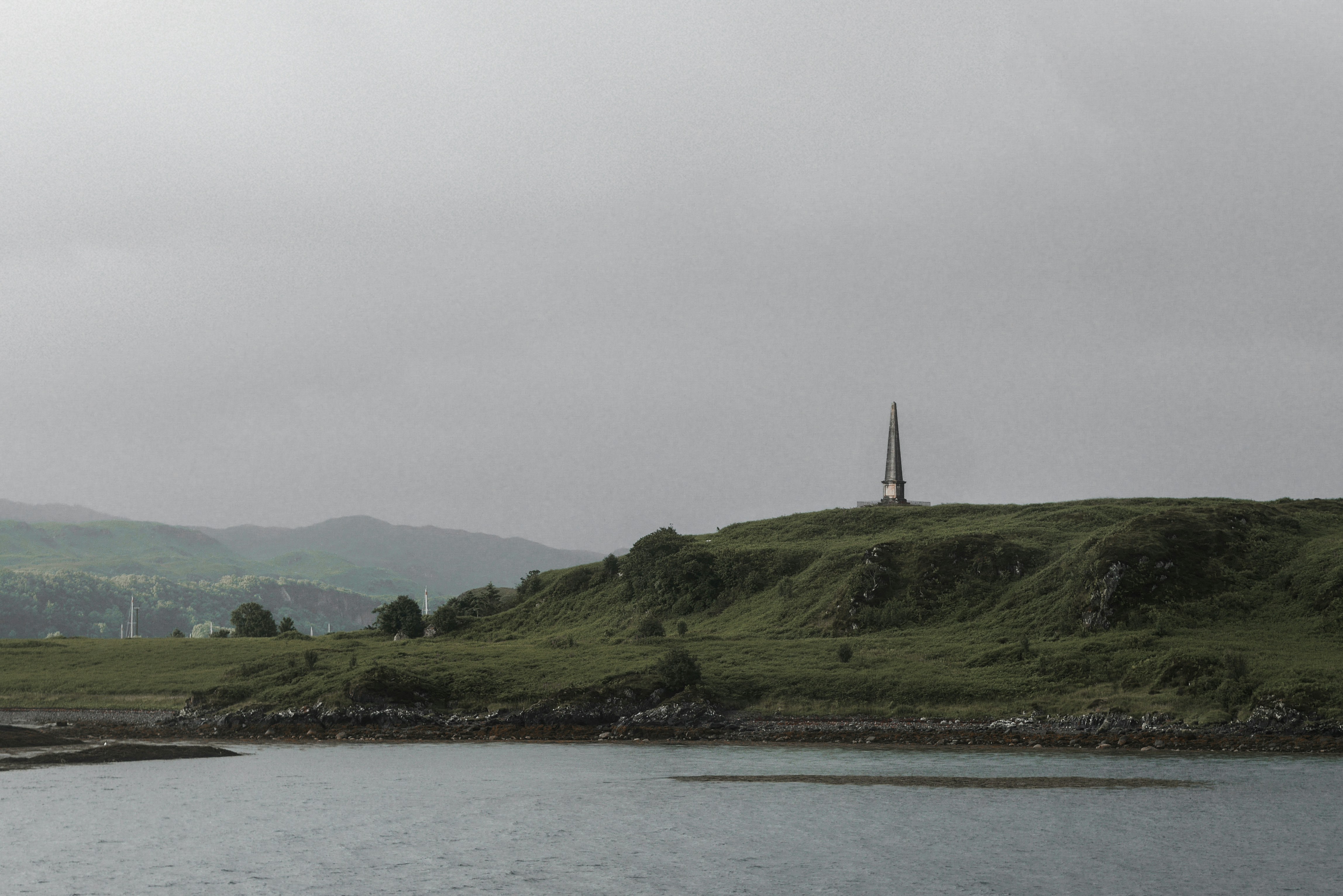 white sailboat on sea near green mountain during daytime