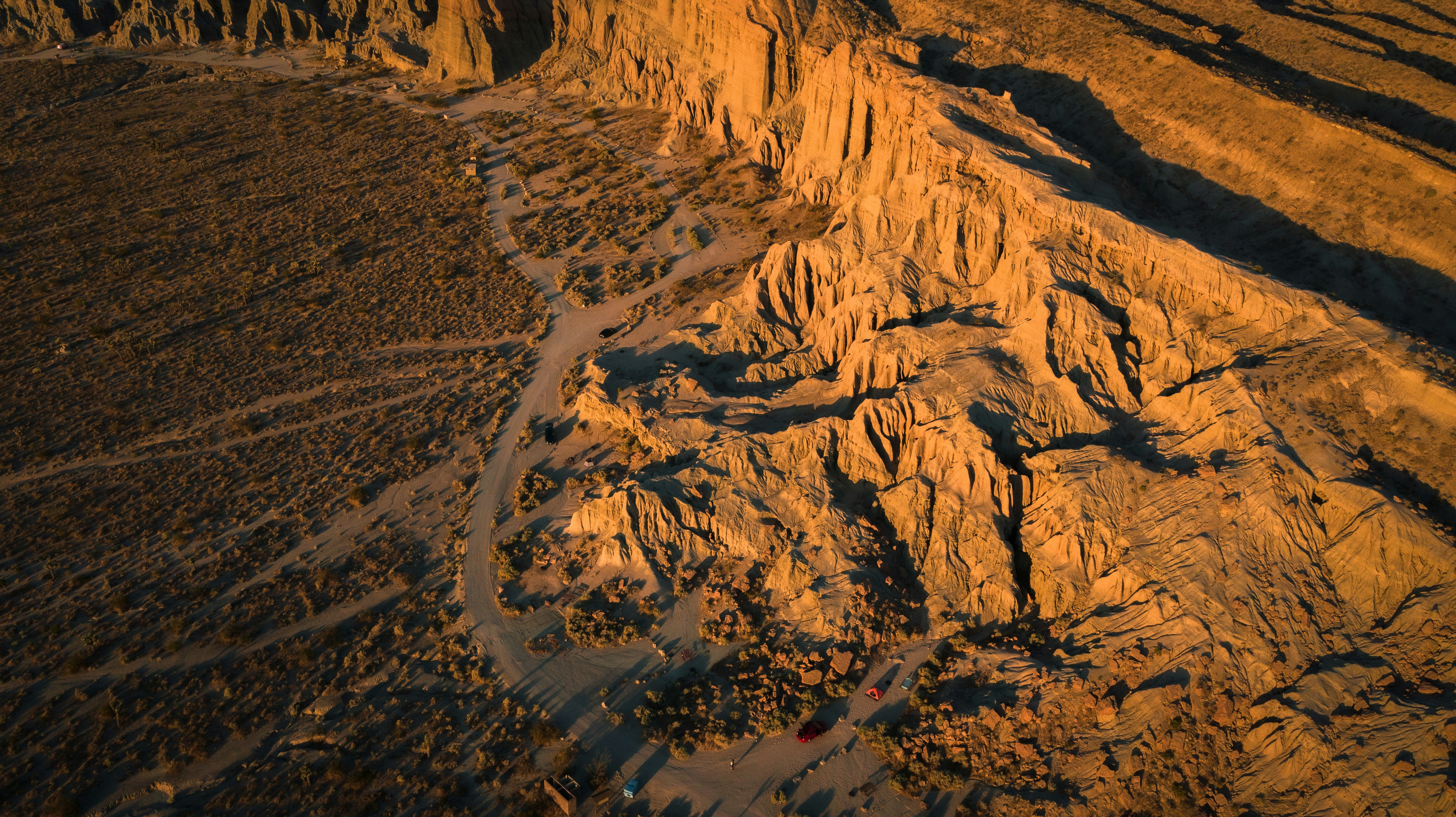 Dramatic rock formations and winding paths in a sunlit desert landscape, showcasing natural erosion patterns.