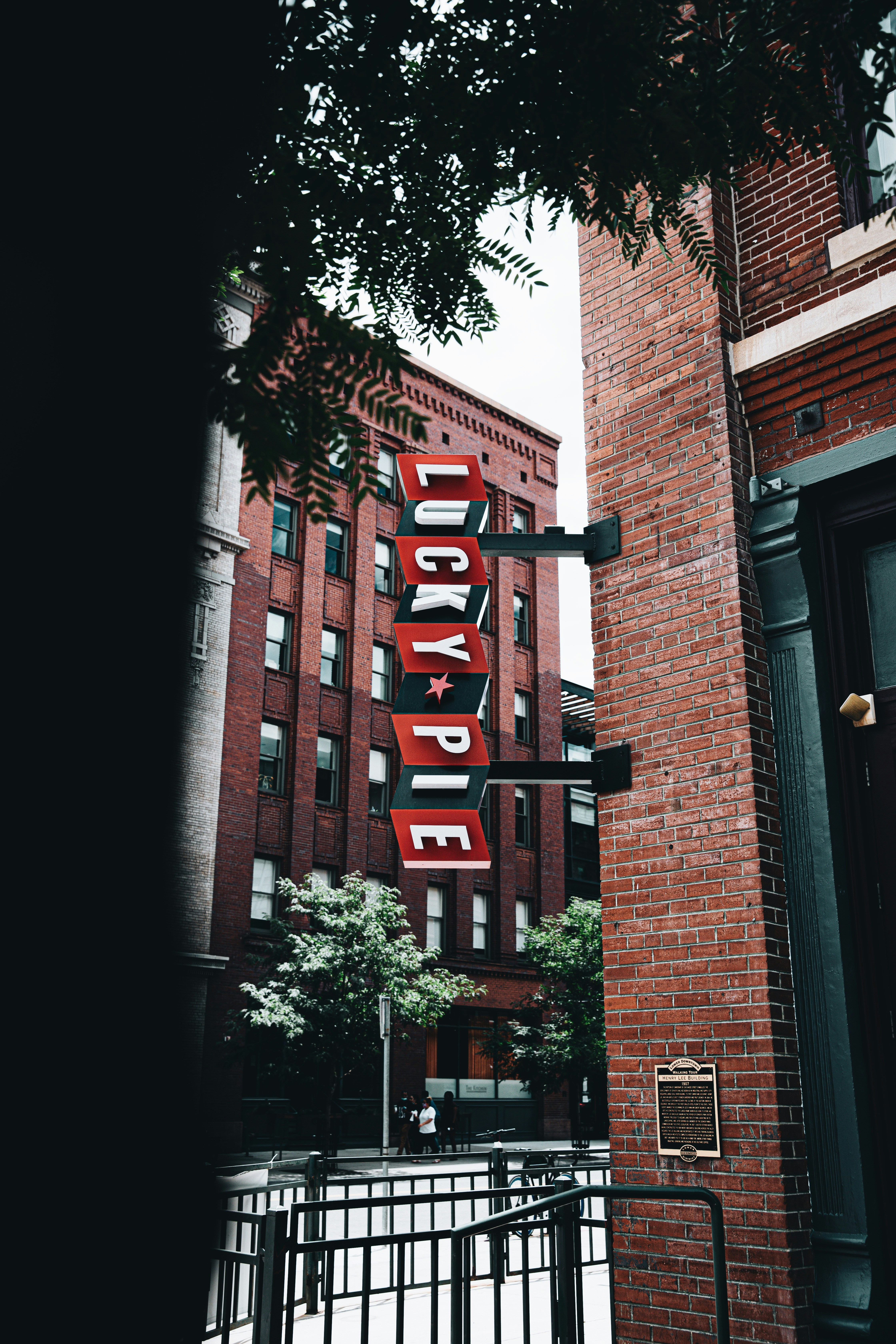 Brick-walled Street Sign: A vertical 'LUCKY PIES' beacon in urban dusk