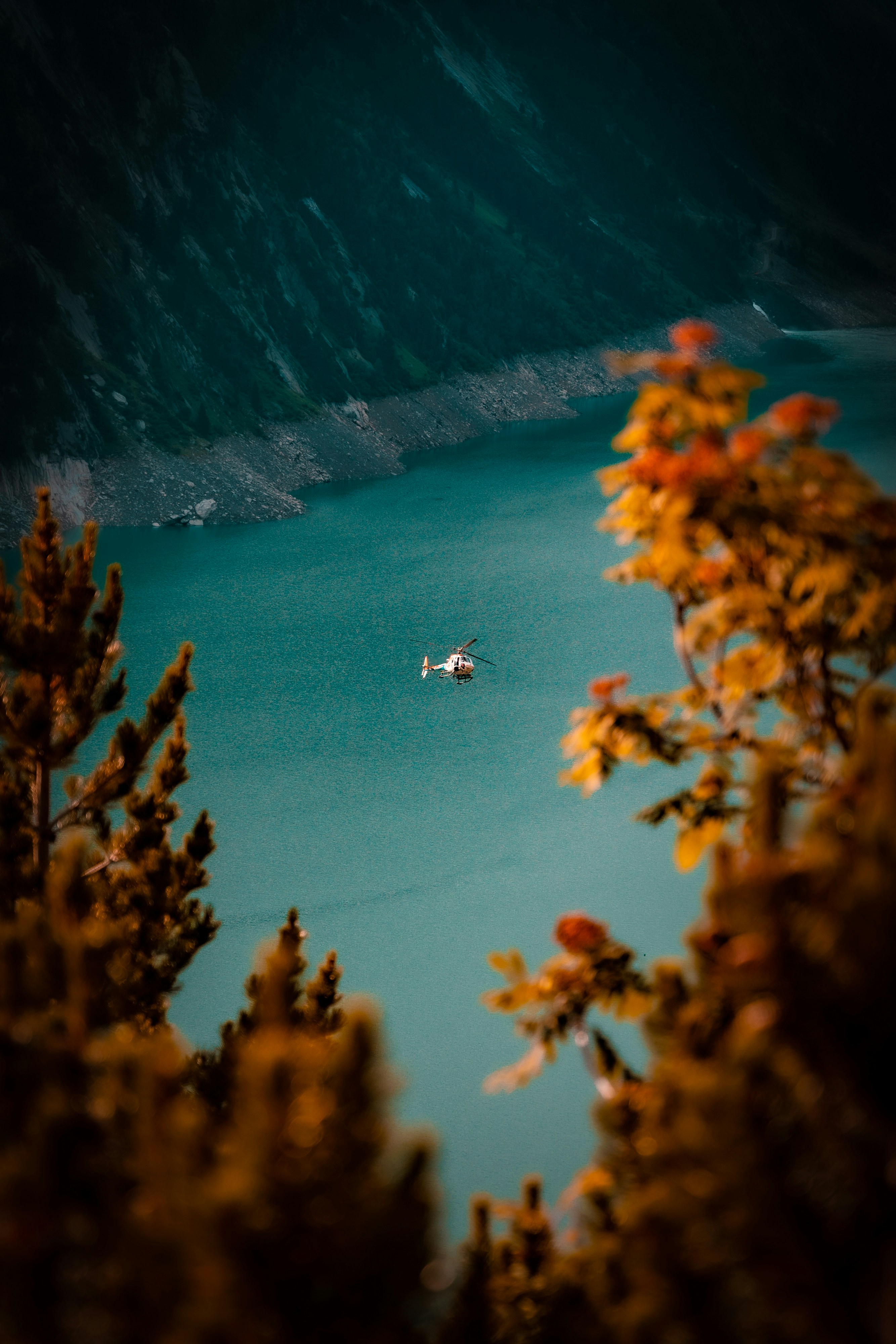 Hovering over turquoise silence: a distant helicopter in a fjord-like valley