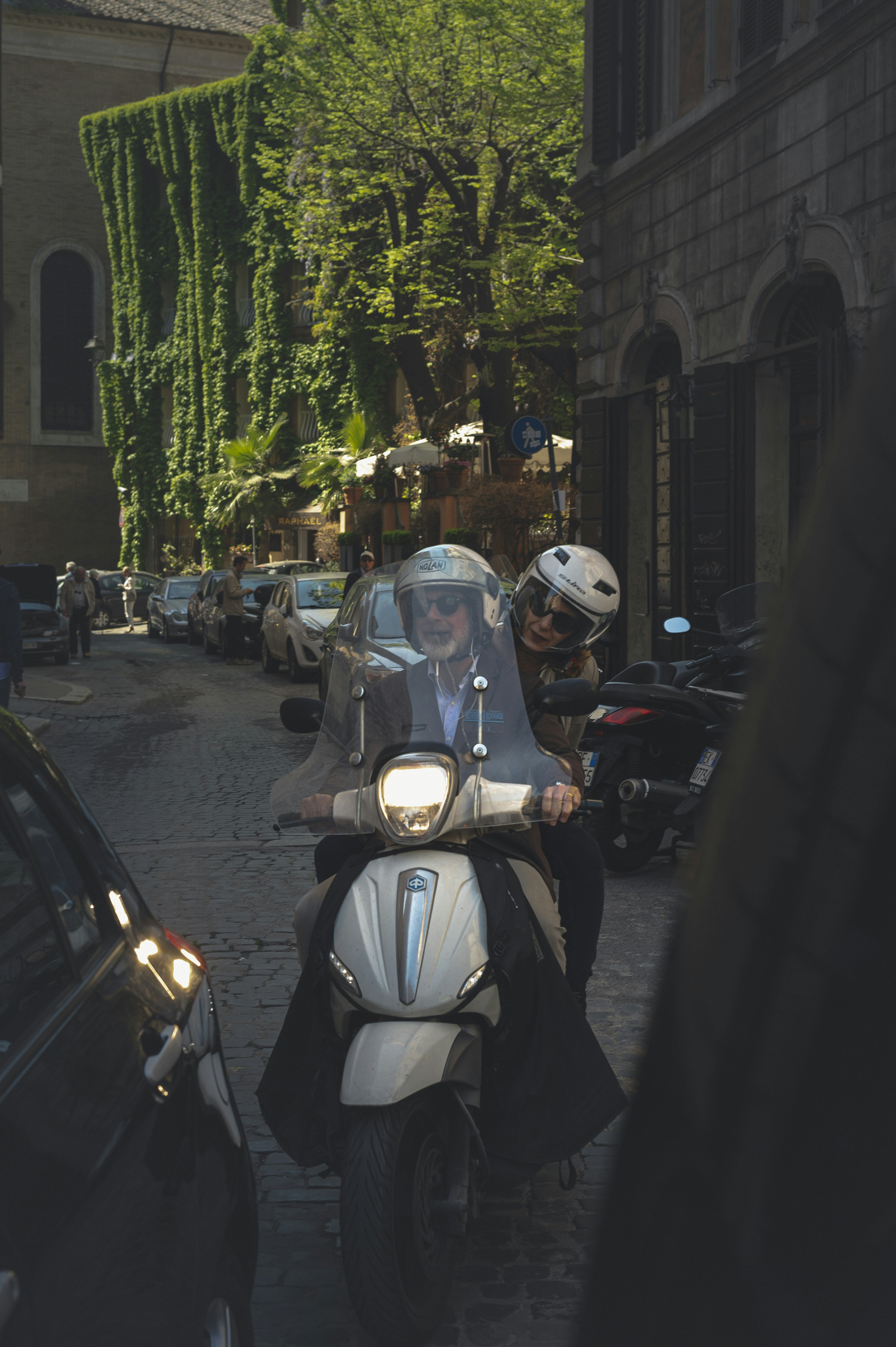 Cobblestone Duo: A Scooter Moment Among Ivy-Hung Facades