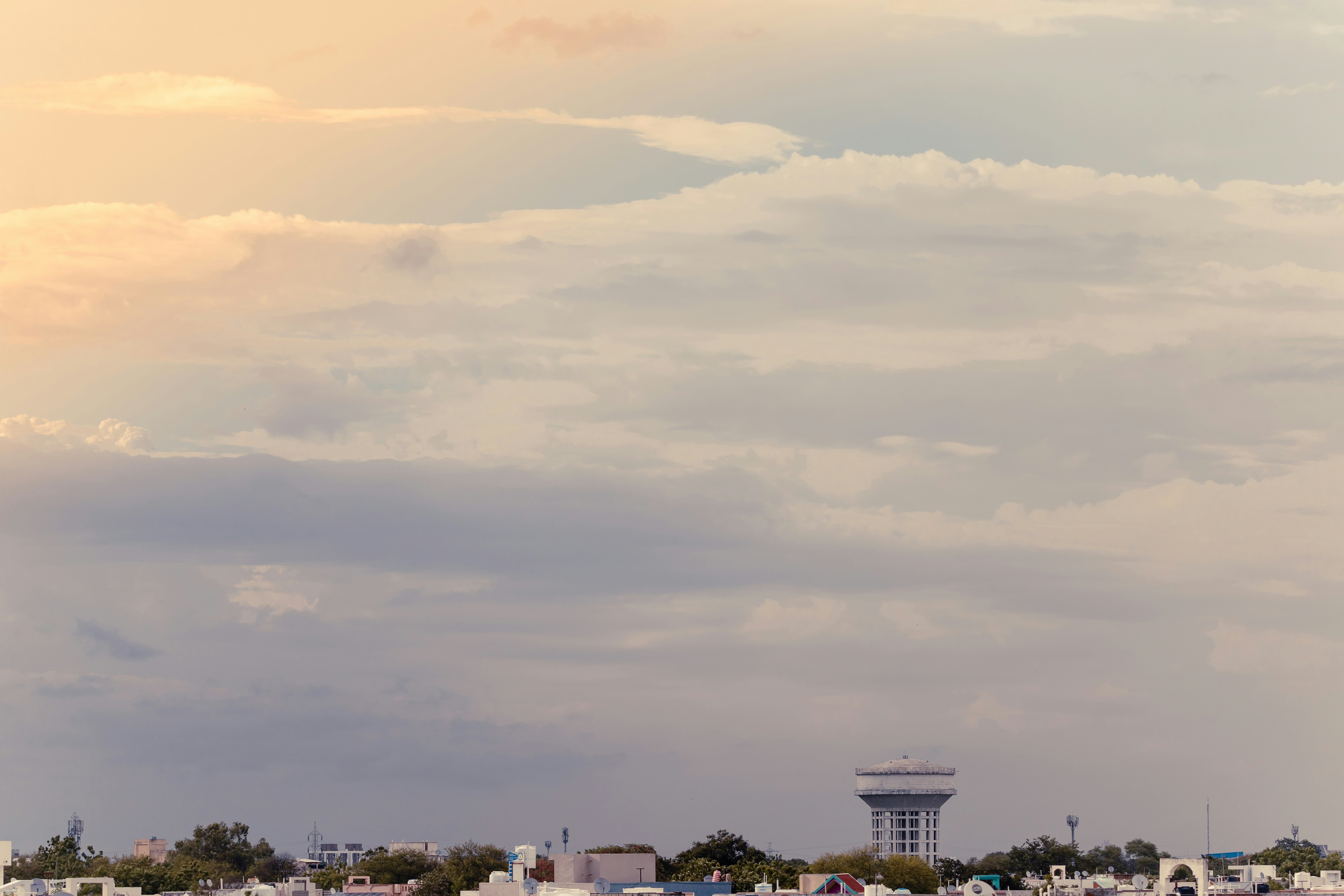 Water tower stands prominently against a backdrop of clouds and a pastel sky, capturing the essence of urban life at dusk.