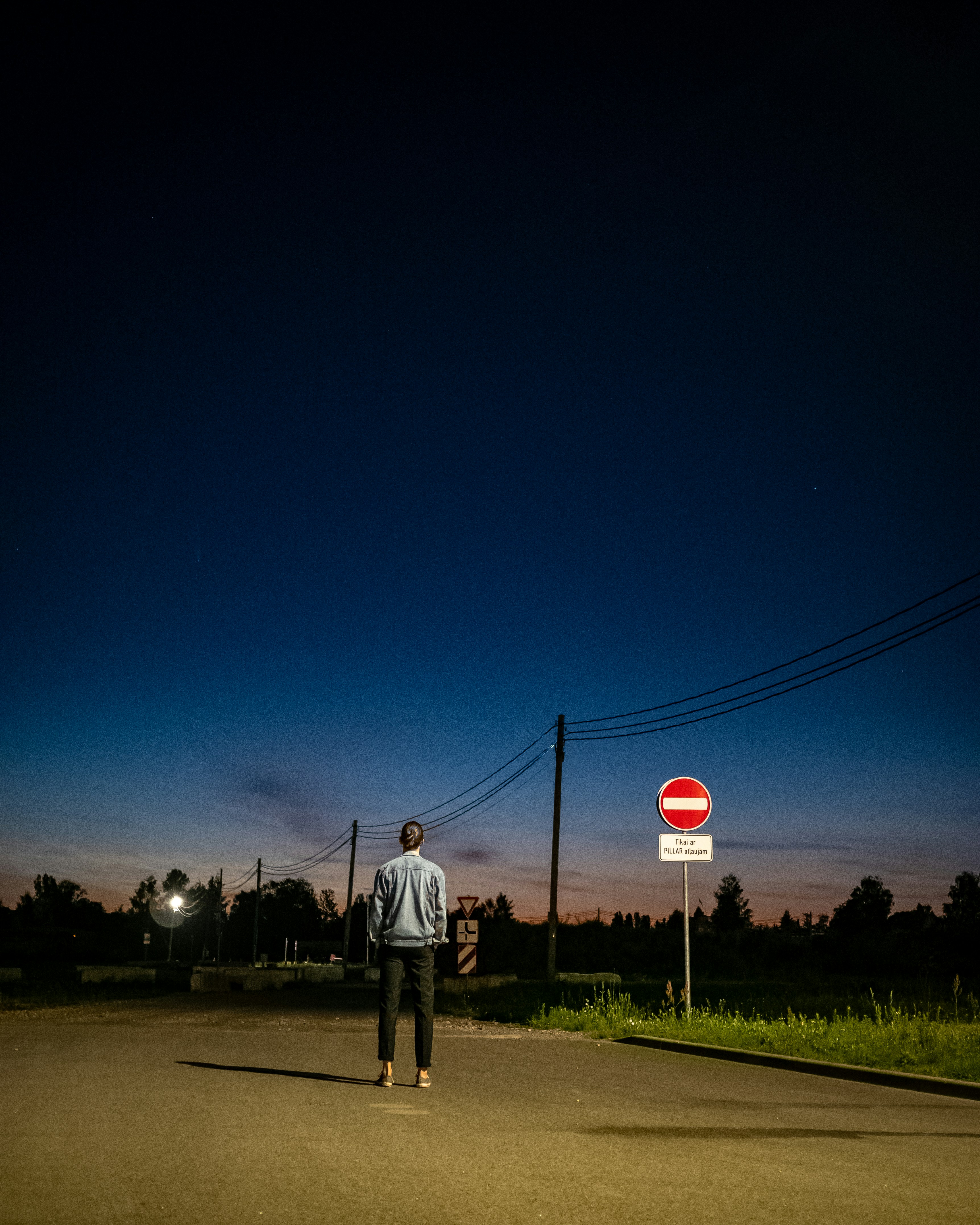 man in white shirt standing on the street during night time