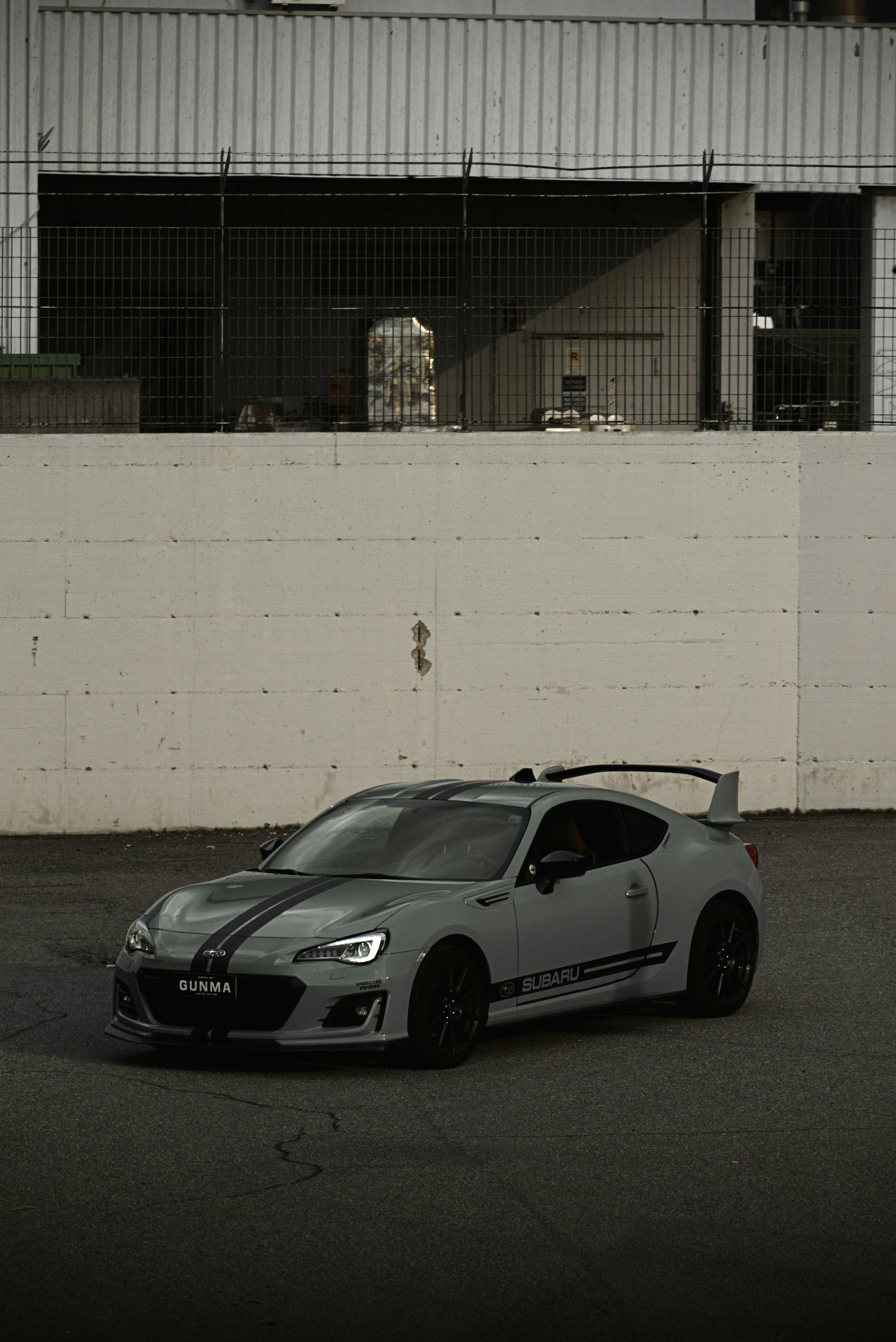 A sleek Subaru BRZ parked against an industrial backdrop, showcasing its aerodynamic design and sporty features.
