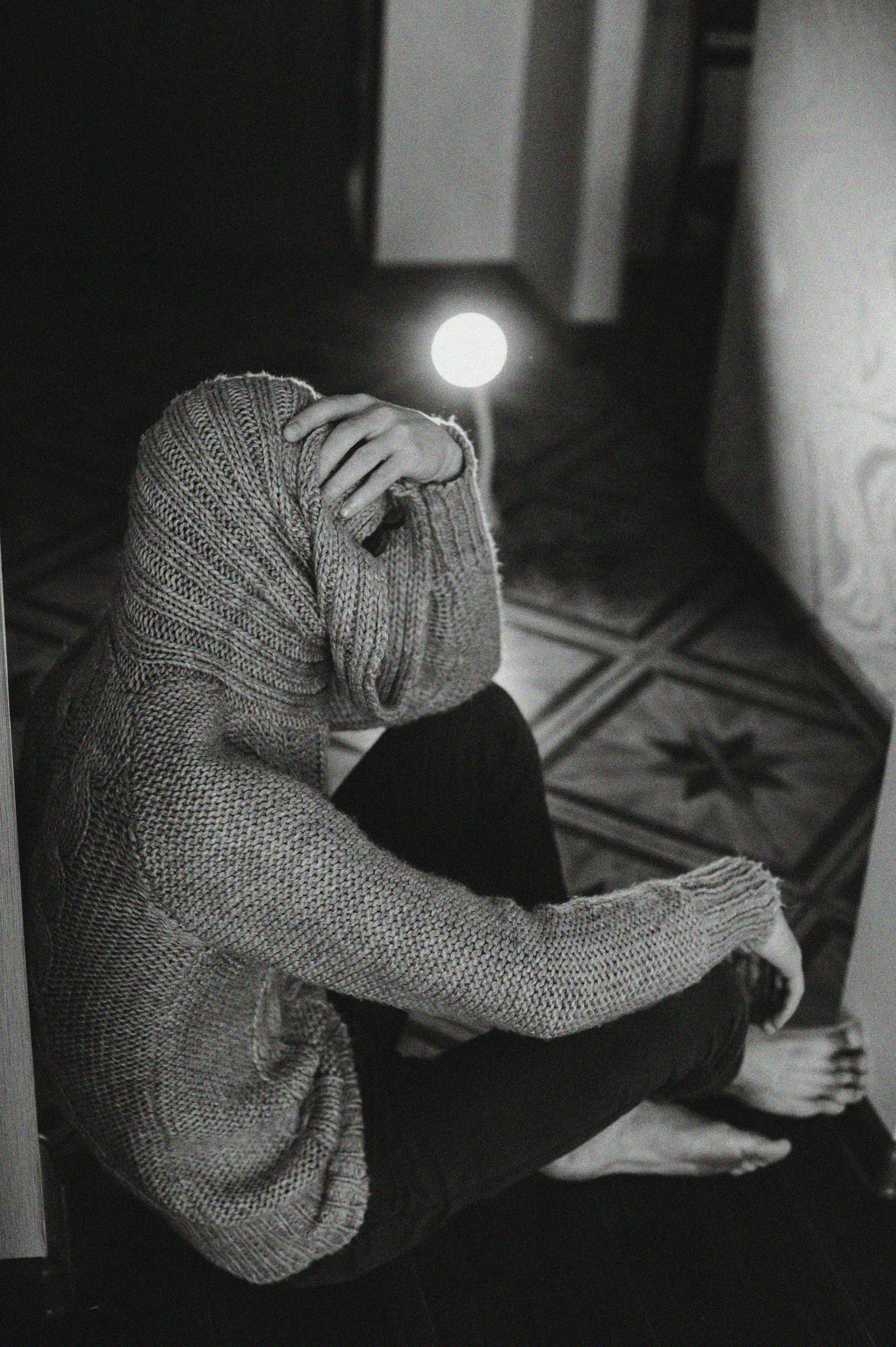 Shadowed Solace: A Knit-Hug in a Dim, Tile-Tiled Corridor