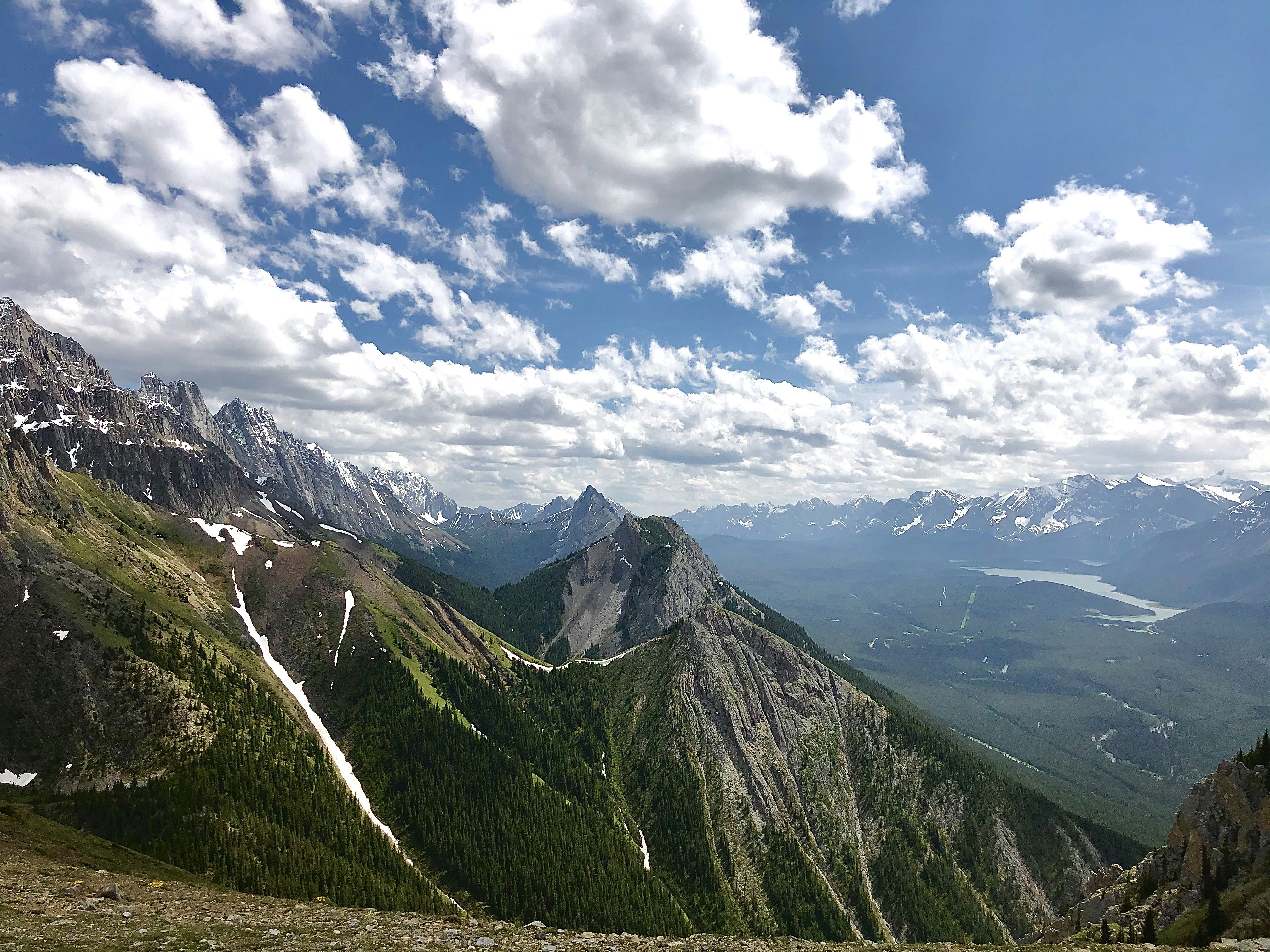 Vast mountain landscape showcasing rugged peaks and lush valleys under a dynamic sky filled with clouds. The scene captures the essence of untouched nature.