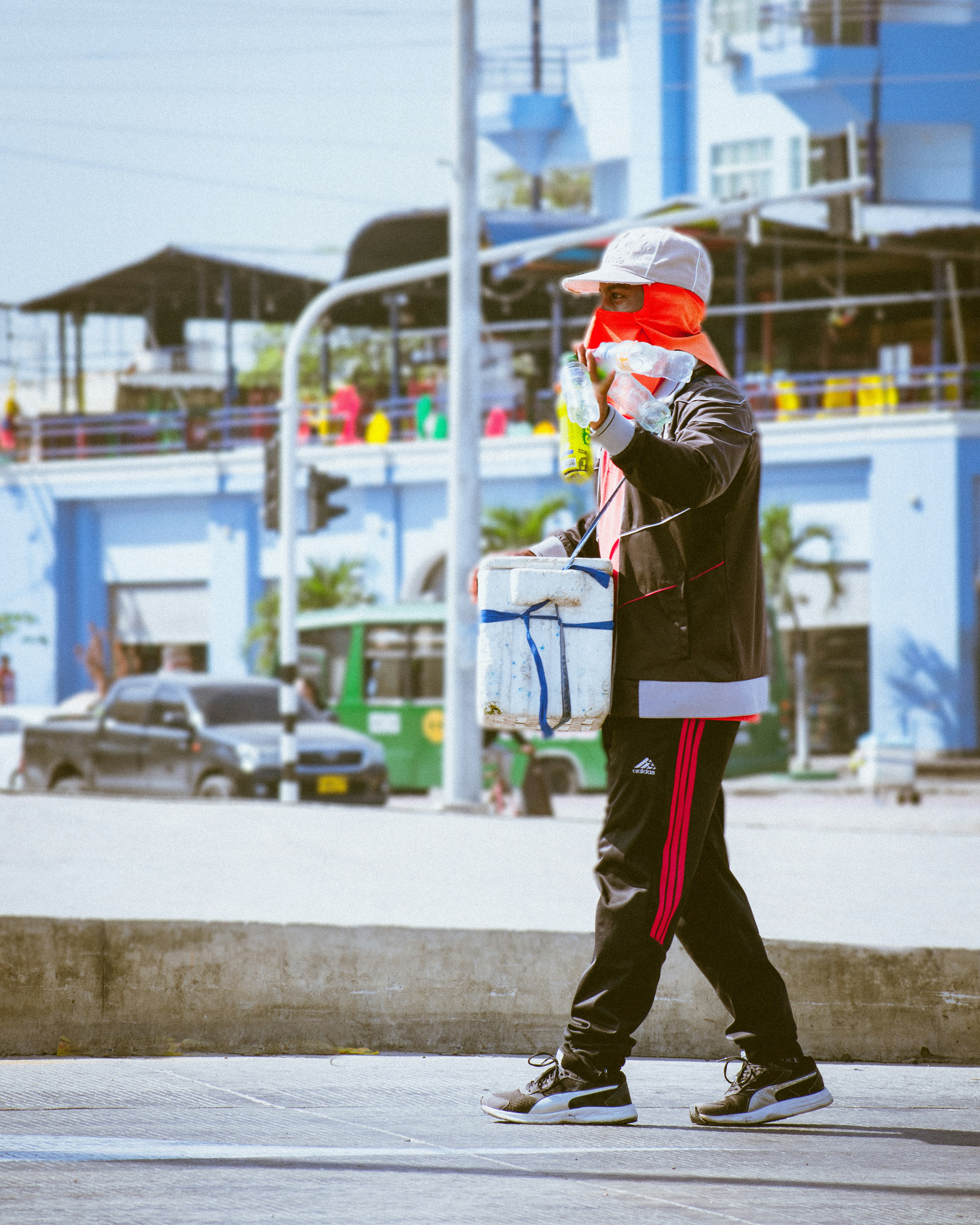 Man in red shirt and black pants wearing red cap standing on sidewalk ...