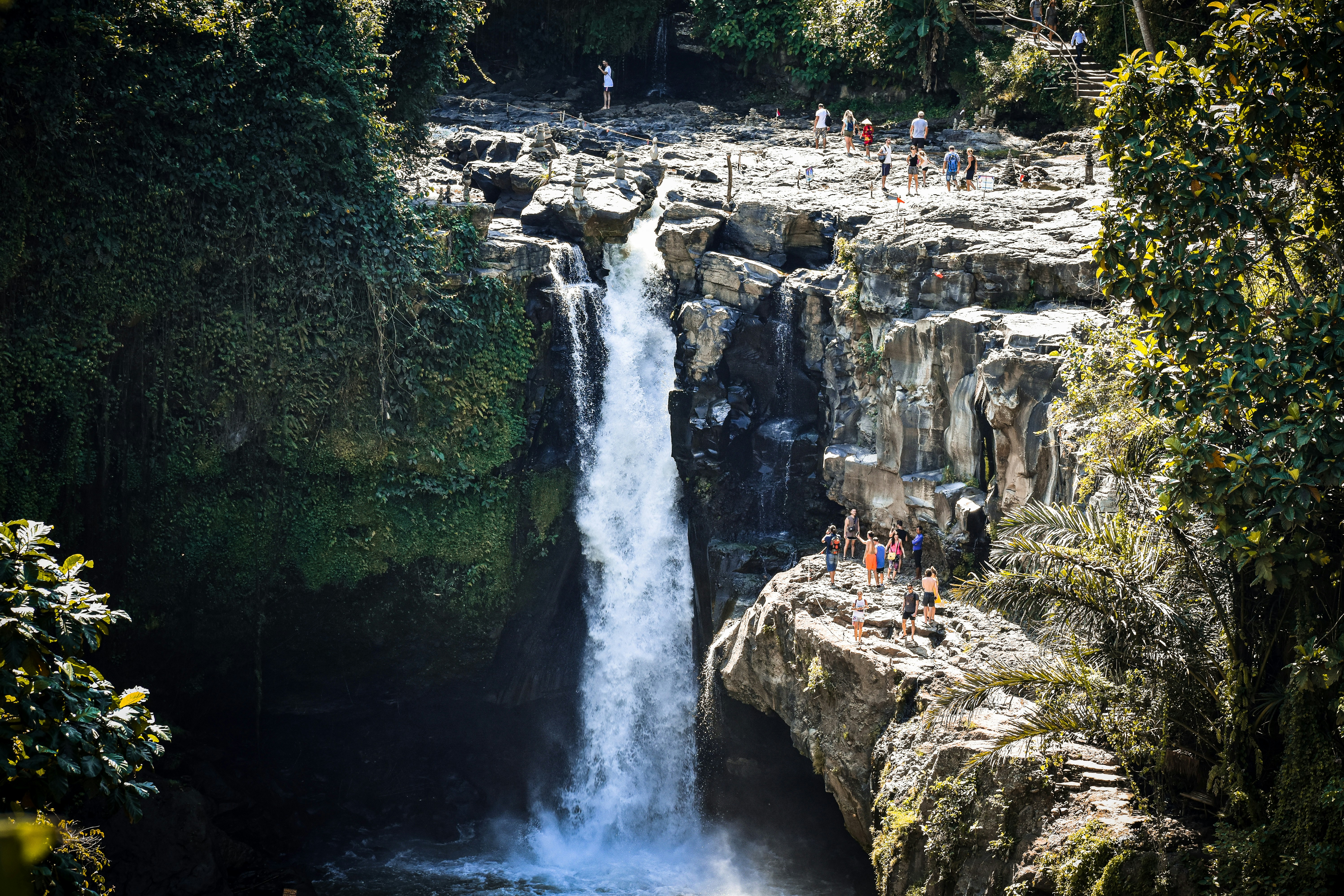 Waterfall cascading over rocky cliffs surrounded by lush greenery.