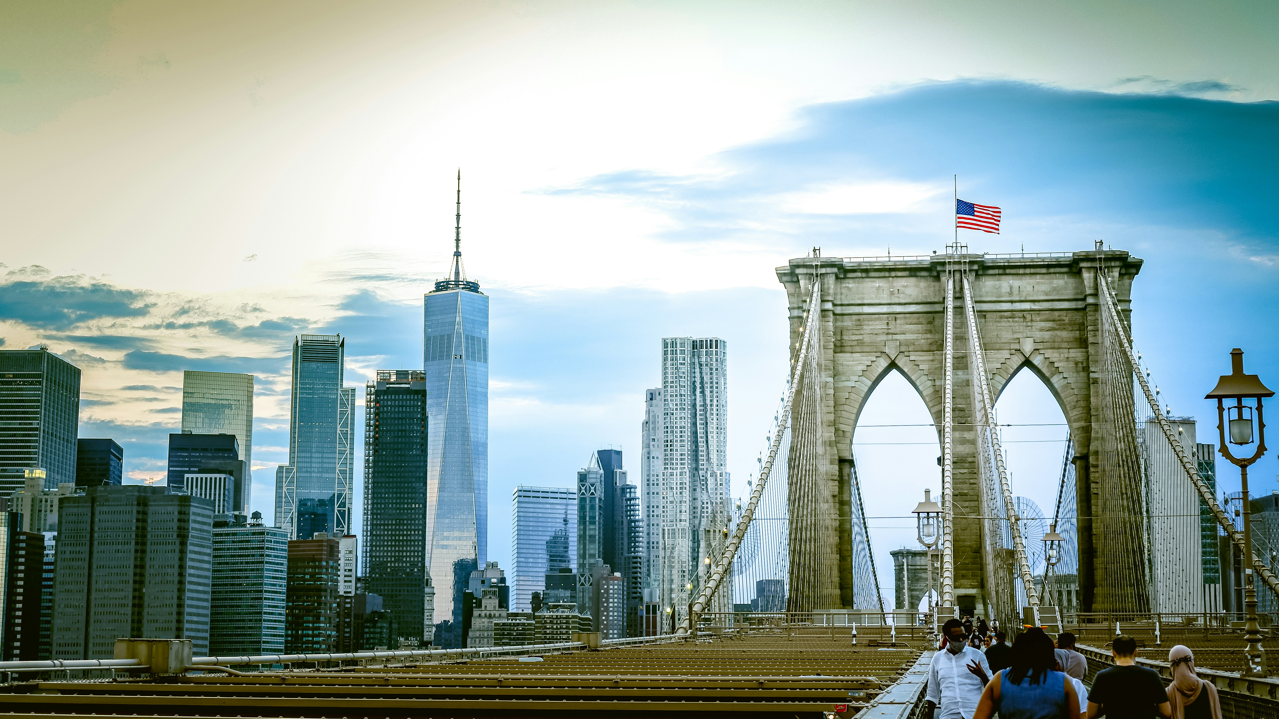Brooklyn Bridge with the Manhattan skyline in the background, showcasing a blend of historic and modern architecture under a cloudy sky.