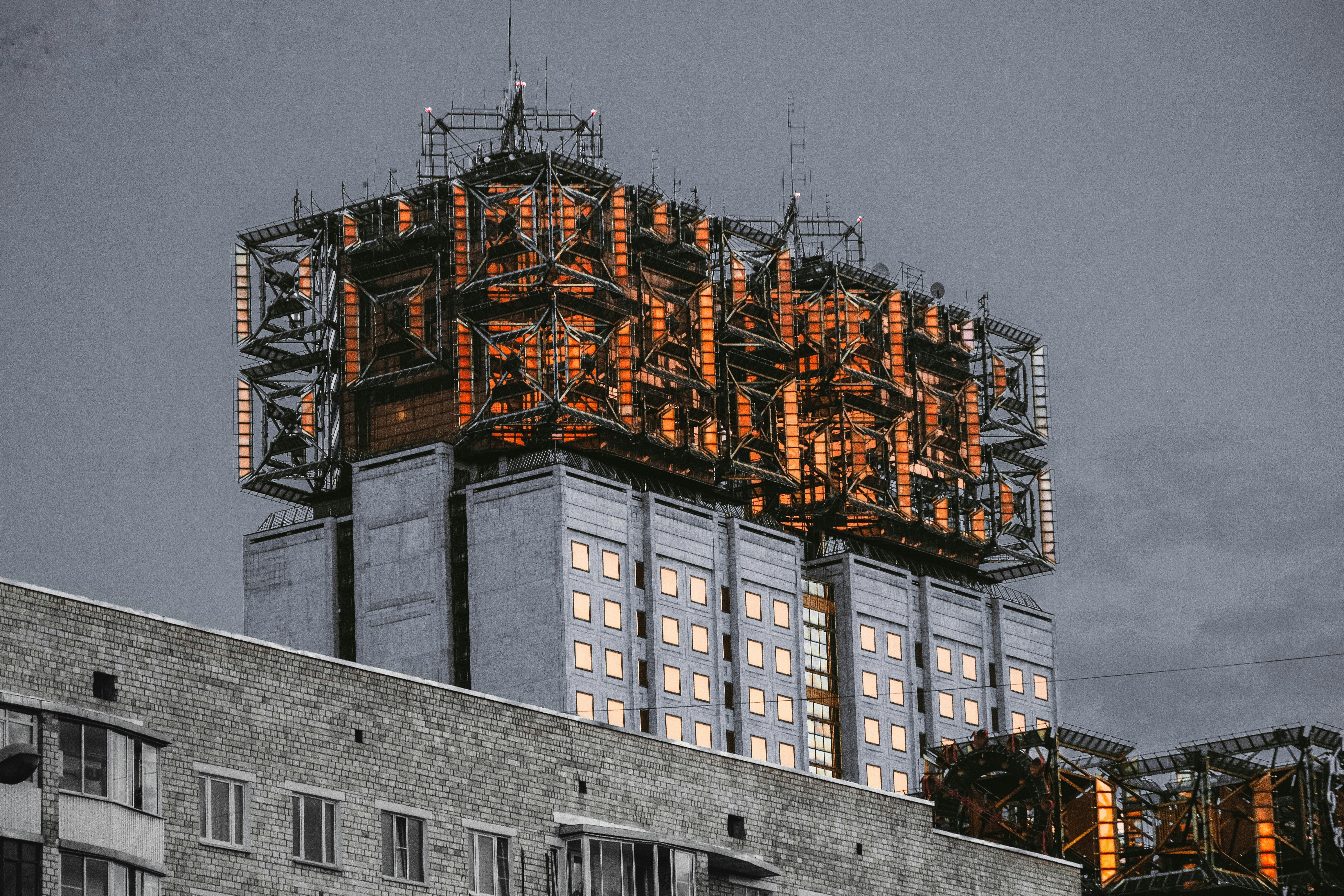A modern building topped with a complex structure, showcasing a blend of architectural design and industrial elements against a muted sky.