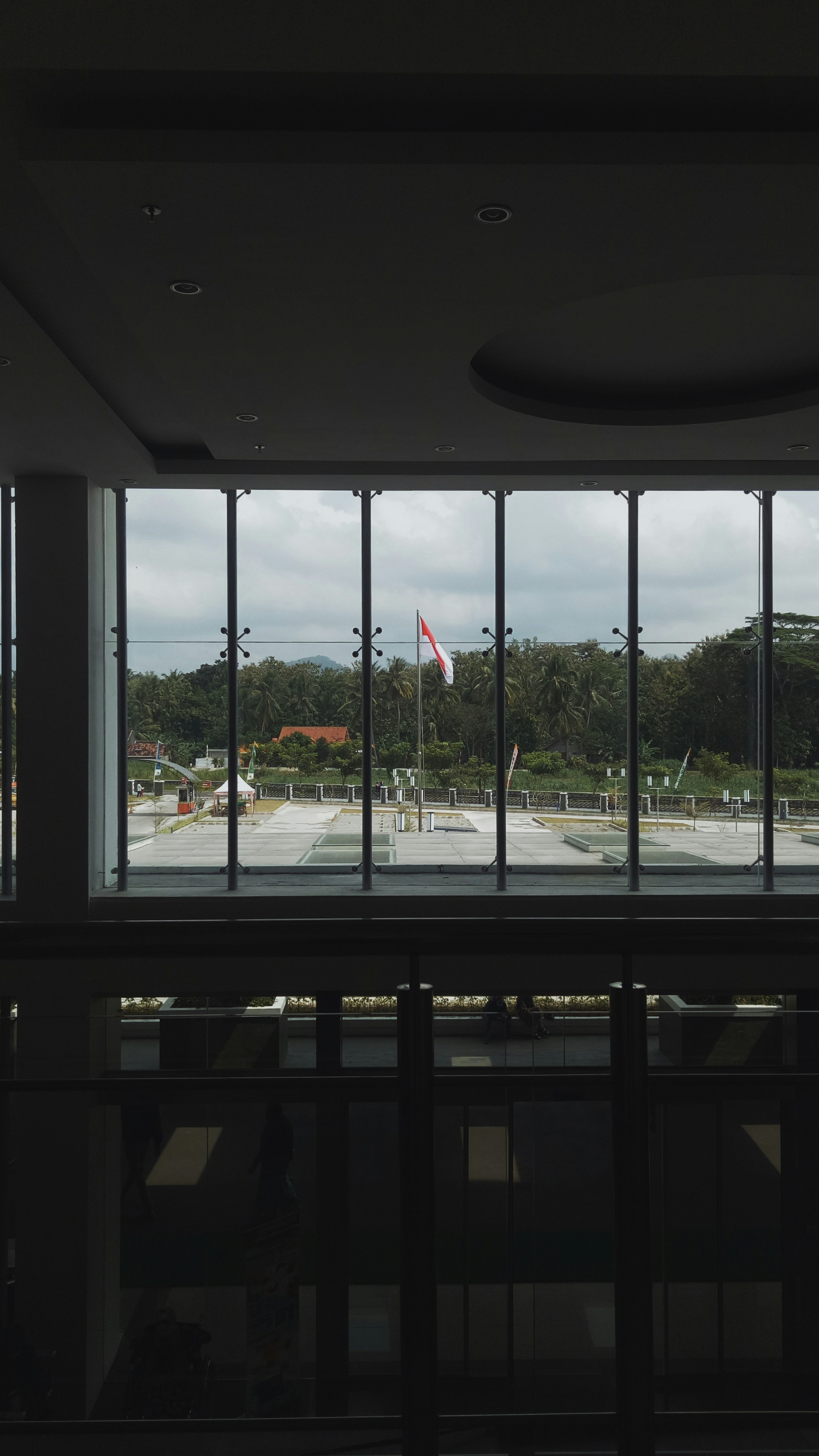 Atrium Vista: The Flag Beyond Glass Framing a Calm Courtyard