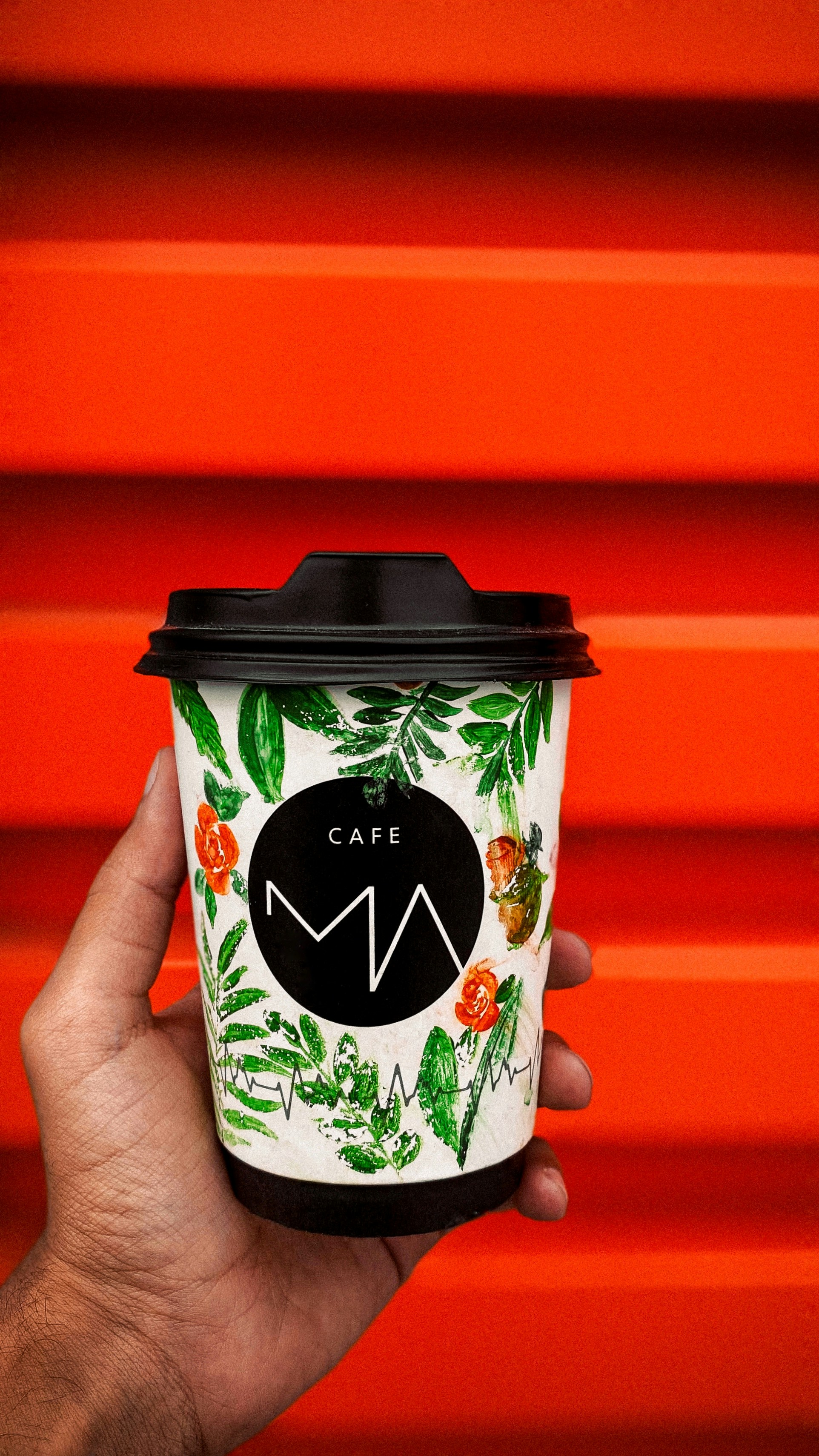 Floral Takeaway Cup Against Neon Orange Stripes