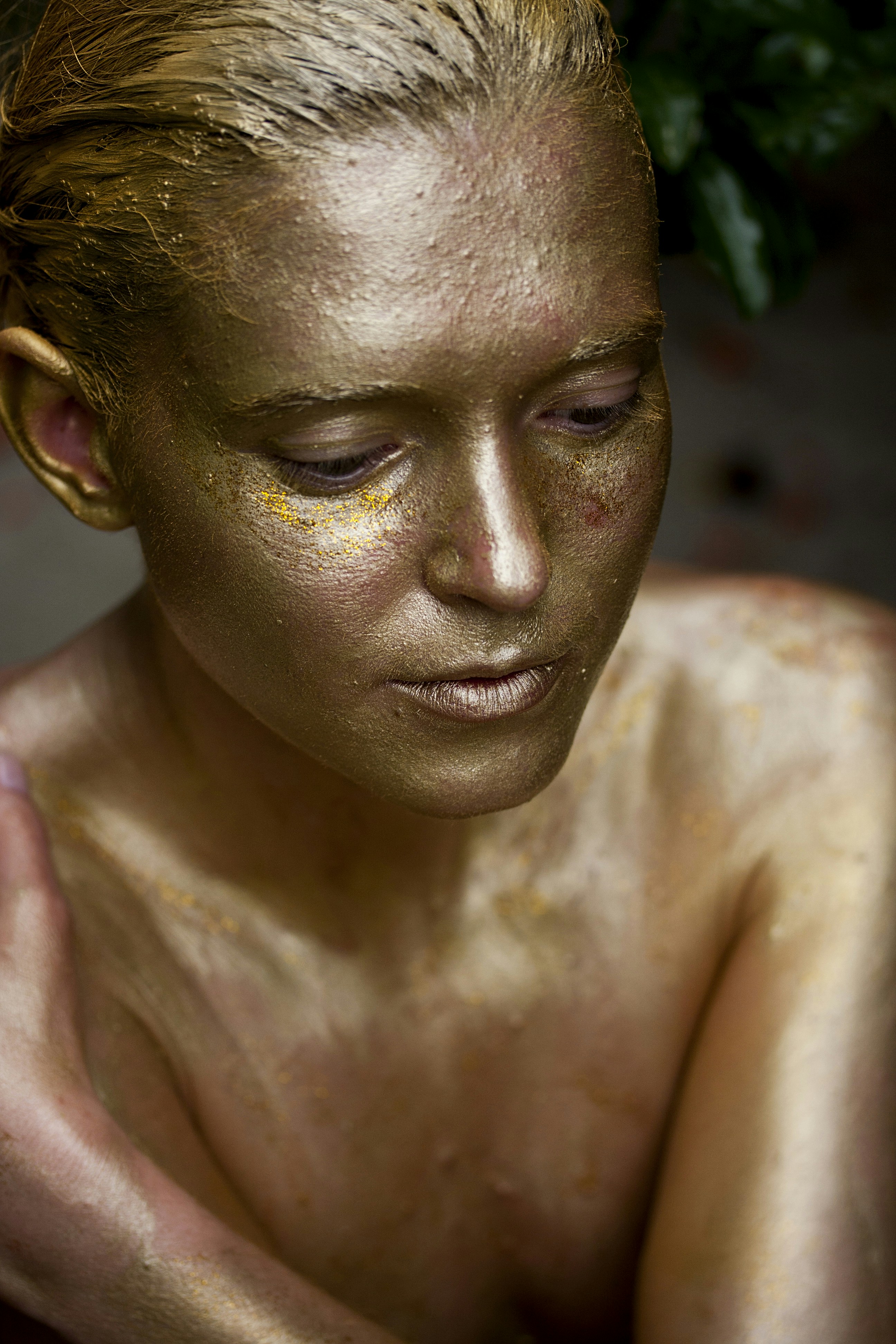 Gilded Quiet: a close-up portrait bathed in metallic skin tones