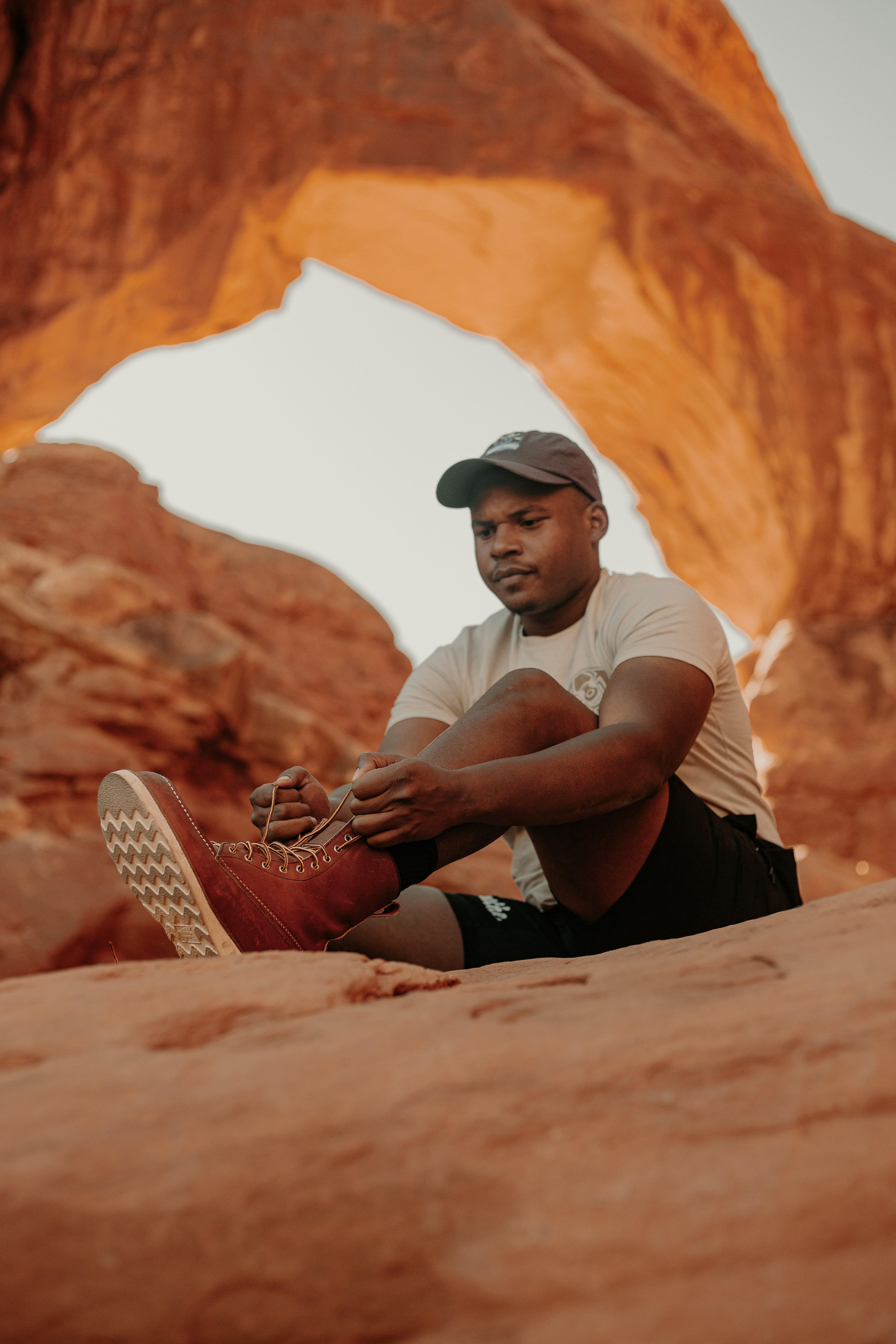 Boots on the Red Sand: A Quiet Moment Beneath the Desert Arch