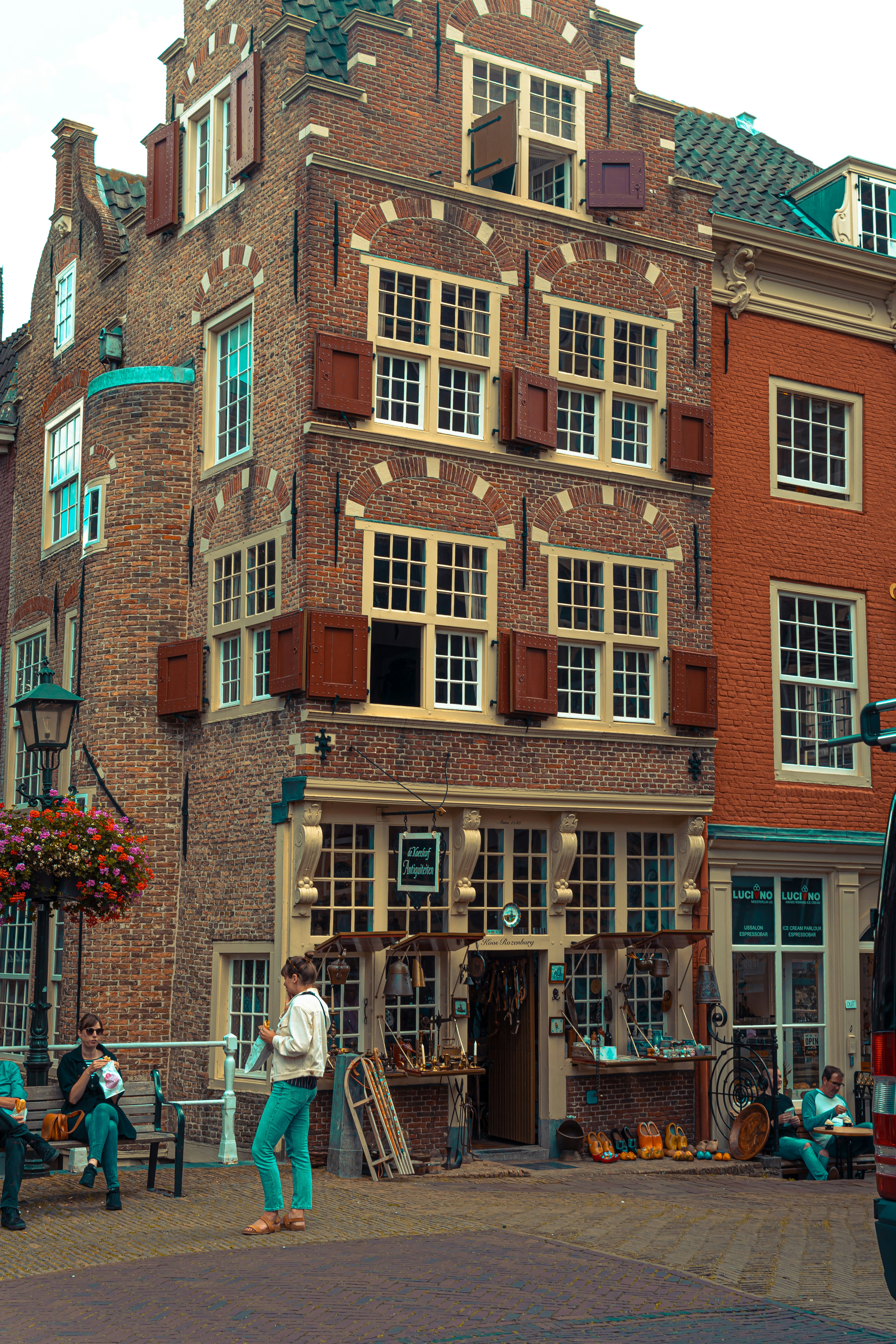 A historic brick building with wooden shutters and large windows, showcasing local craftsmanship in a lively town square.