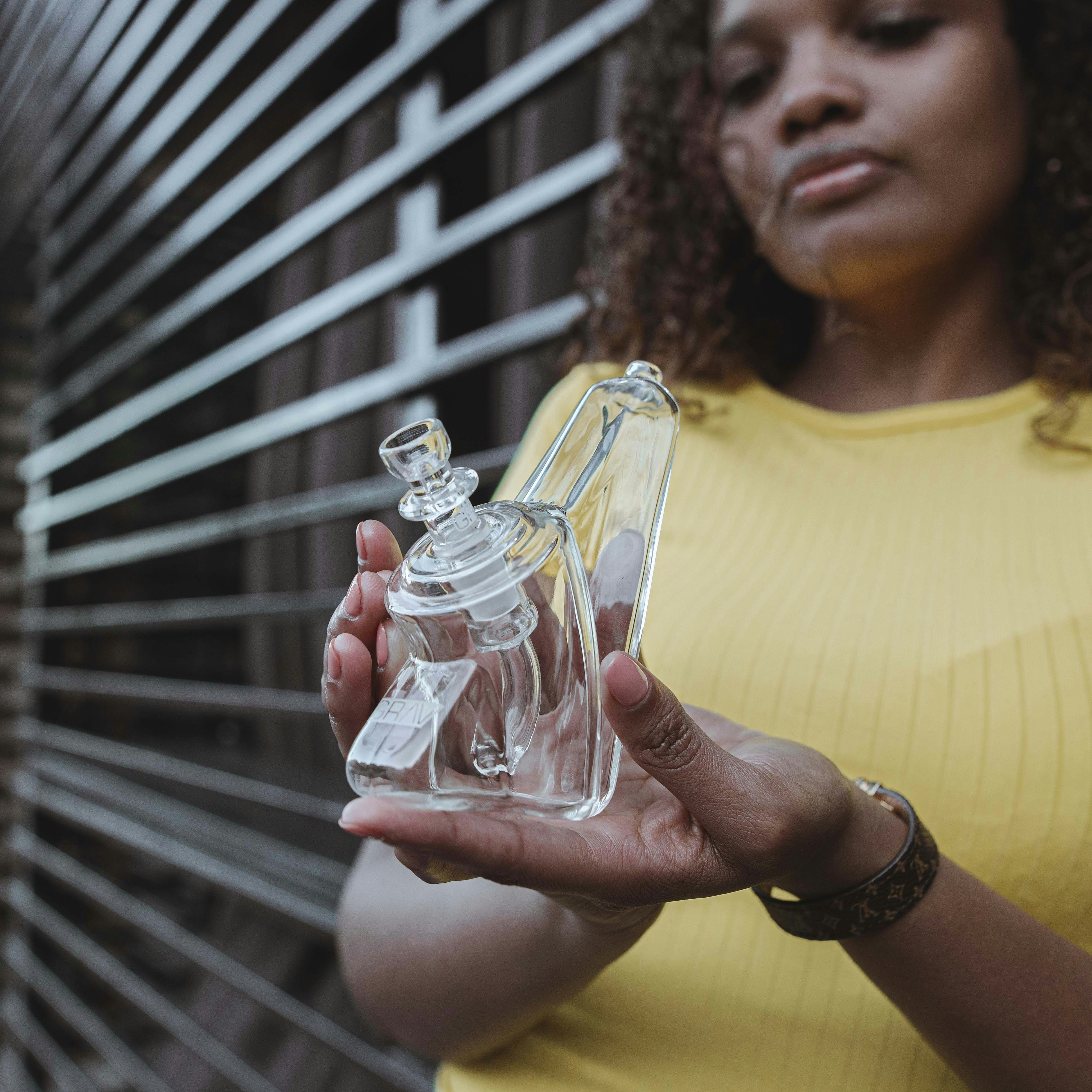 woman in yellow tank top holding glass perfume bottle