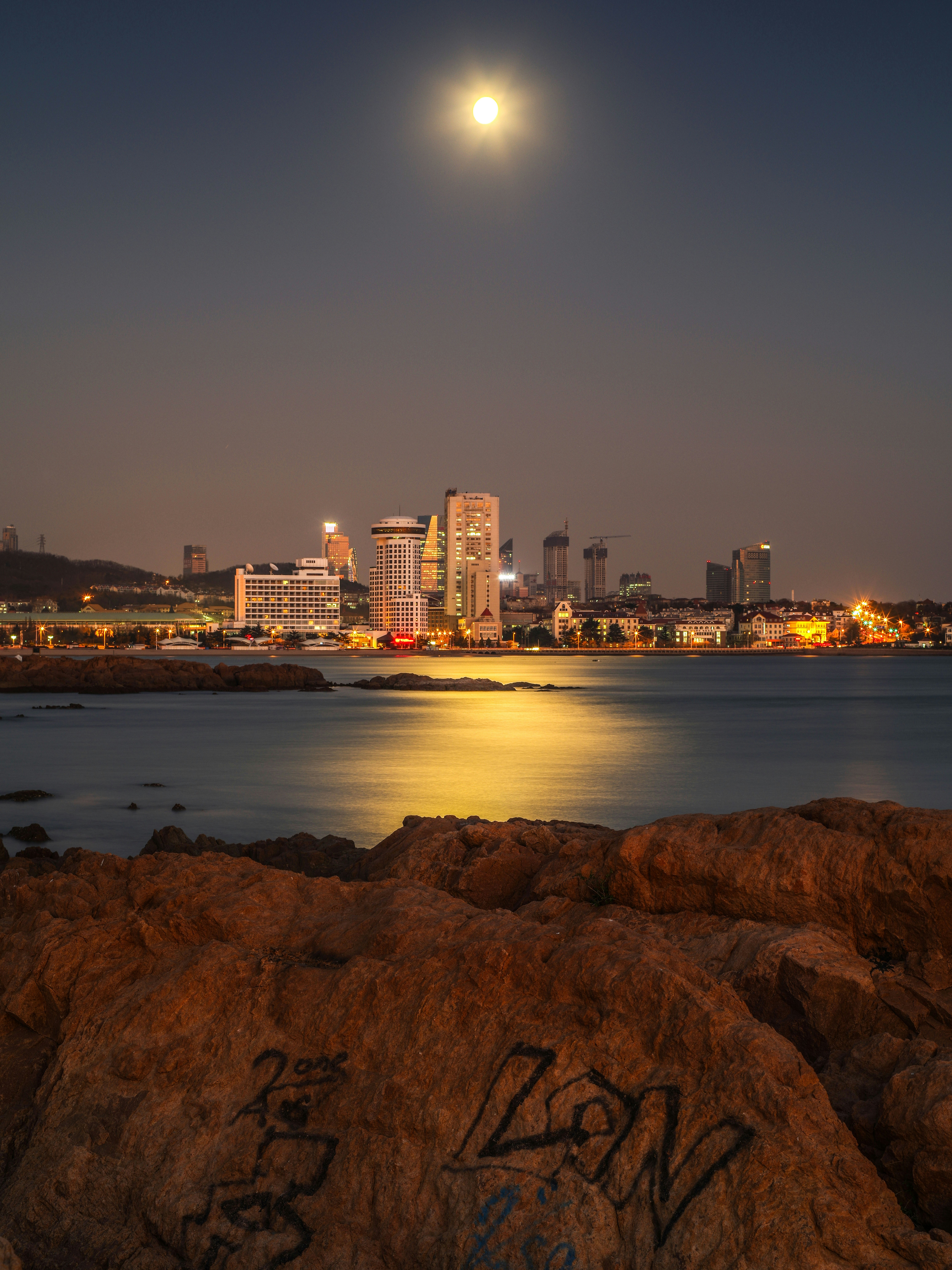 city skyline across body of water during night time