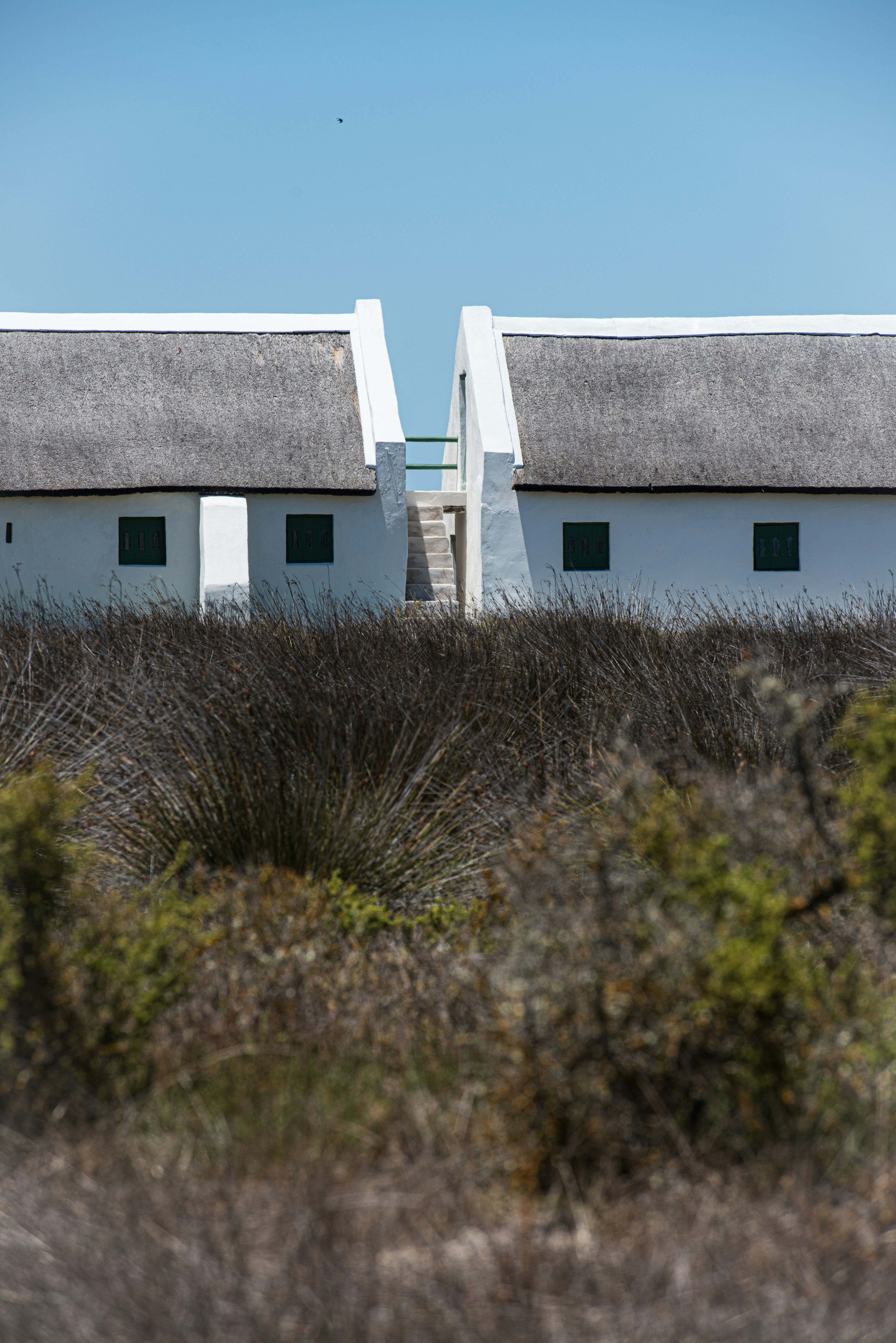 Twin White Cottages with a Central Staircase Under a Coastal Blue Sky