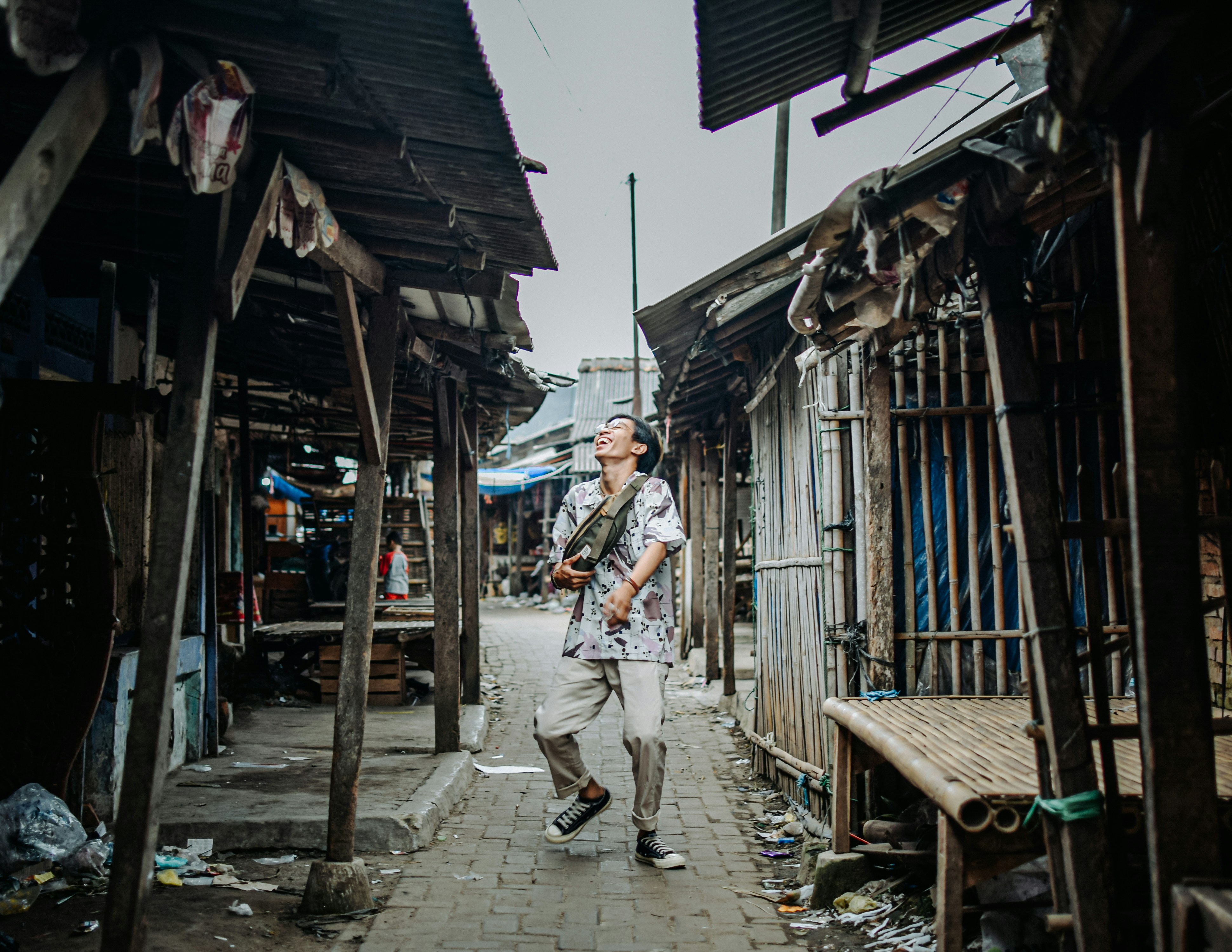 Person in mid-jump on a narrow street lined with rustic wooden structures.