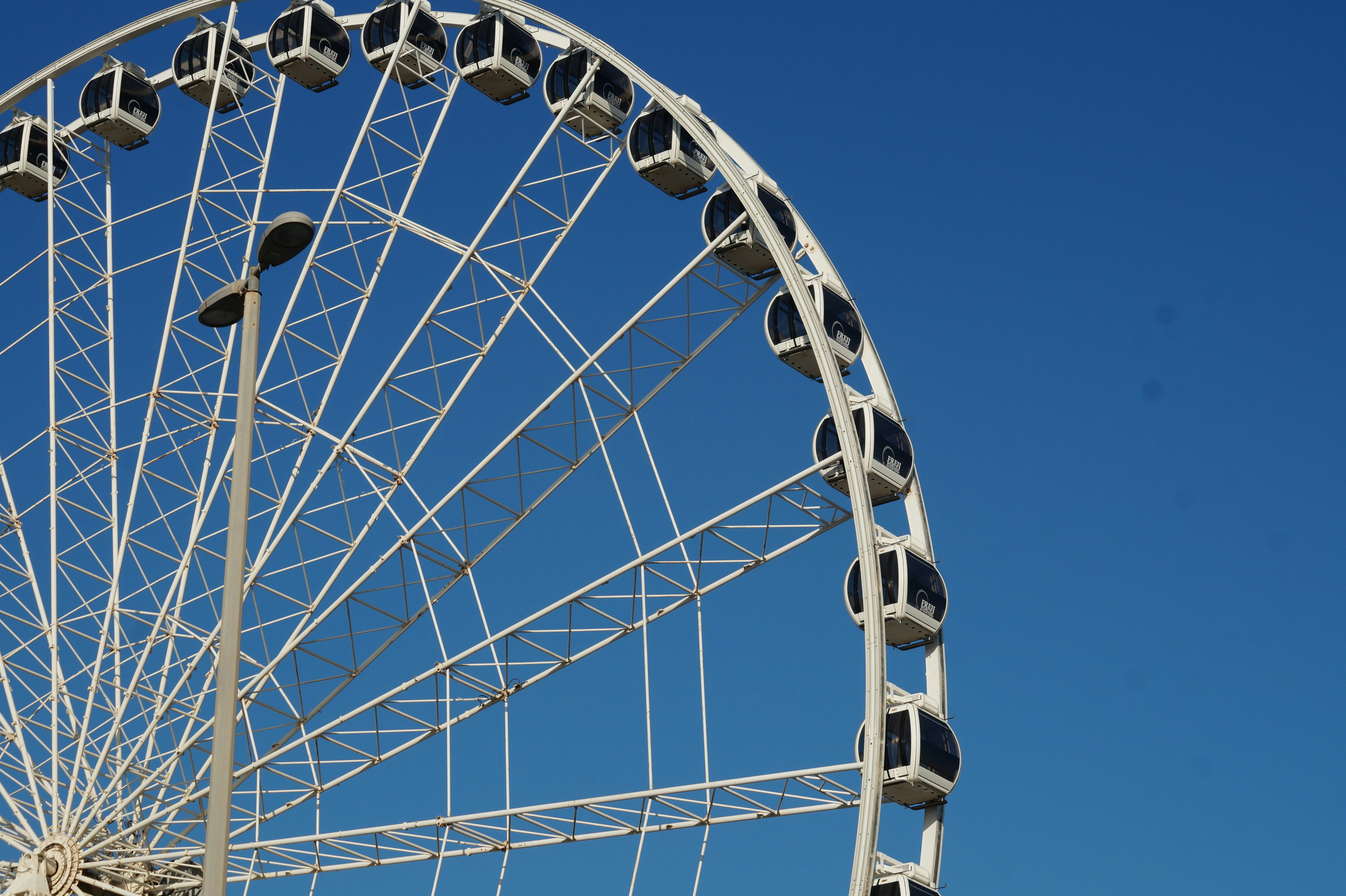 Ferris wheel with white cabins against a clear blue sky.