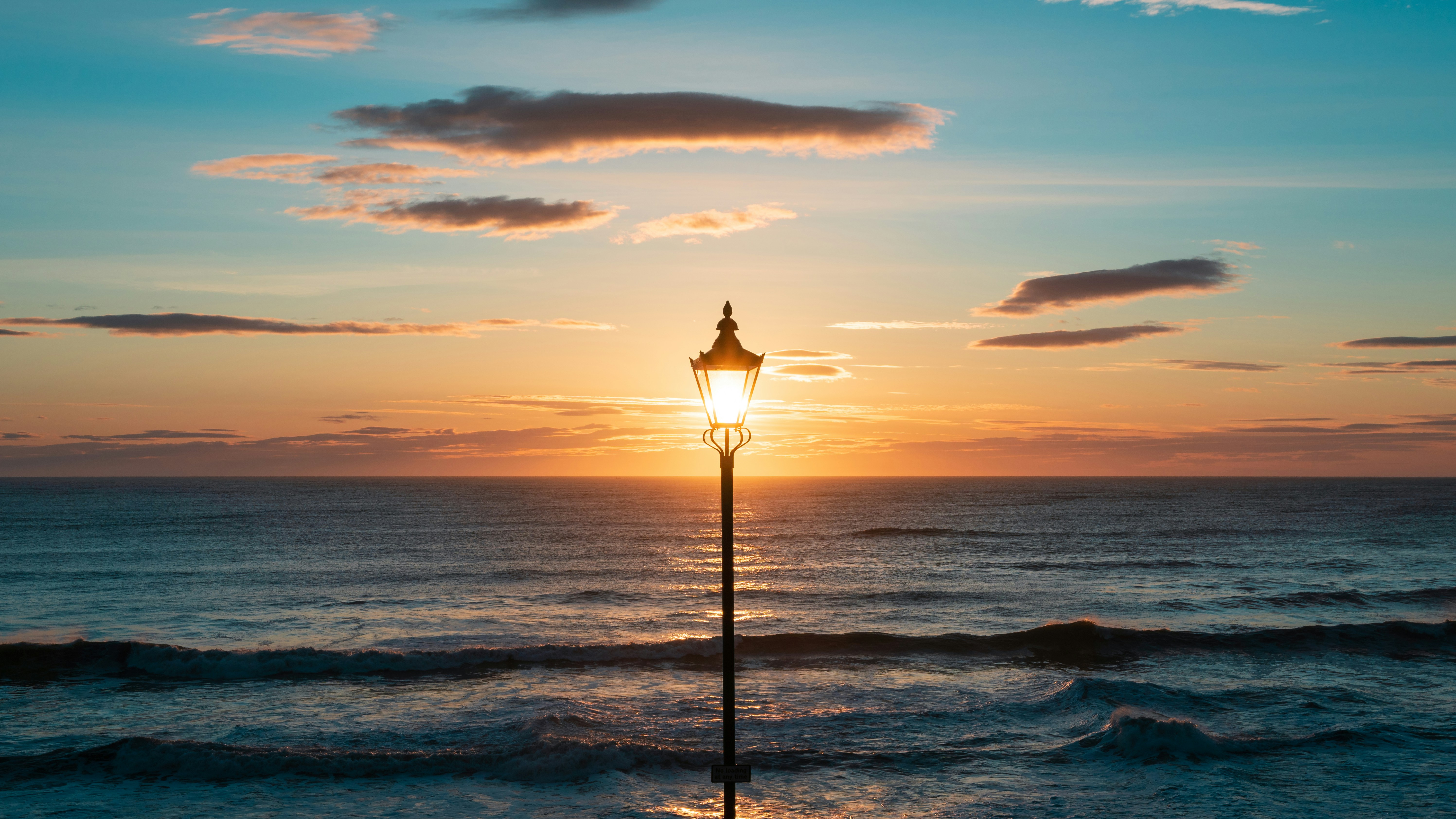 Lamplight at Dusk: A Lone Lantern Framing Sunset Over the Sea