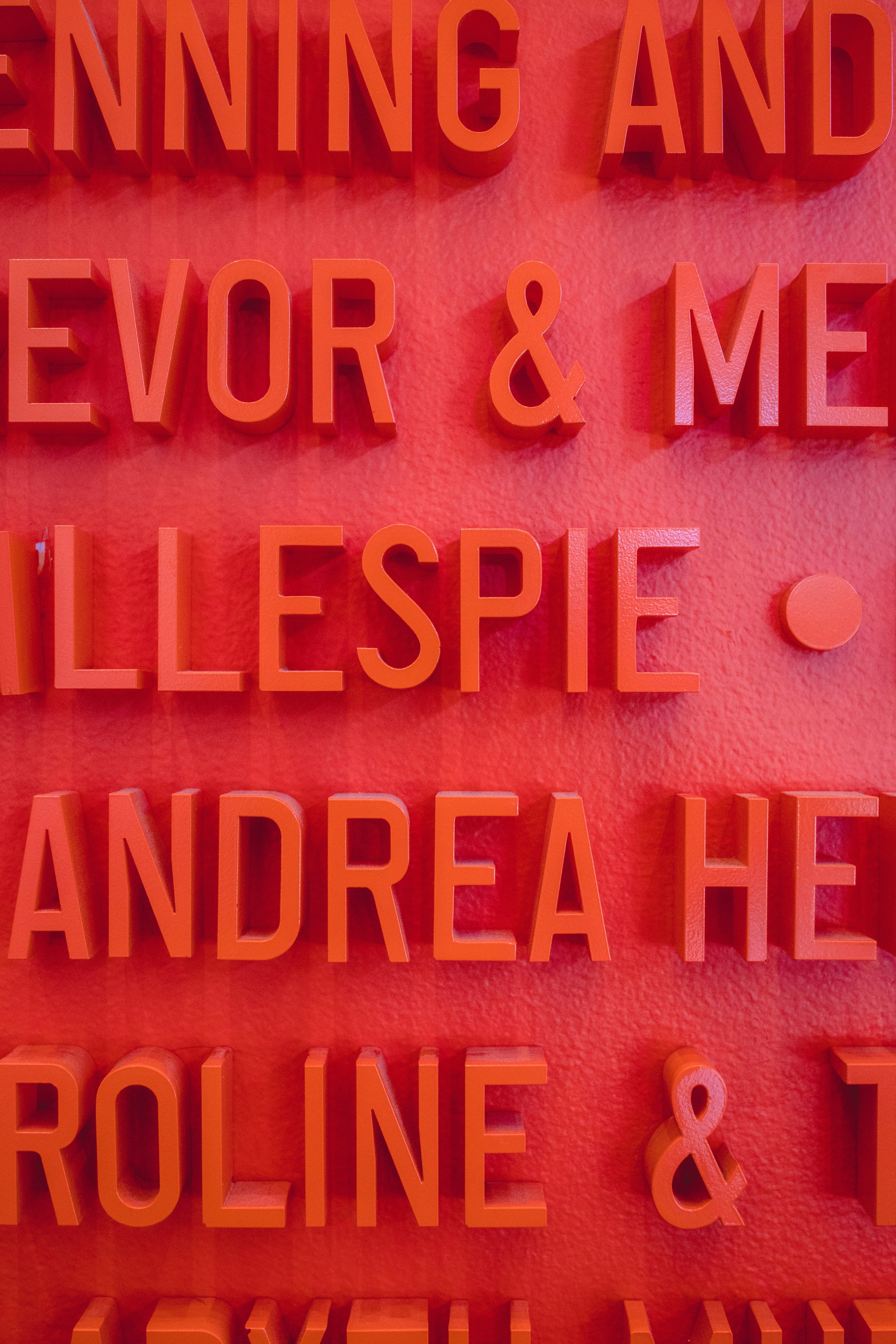 Red Typographic Mosaic: Names in Bold Relief Against a Warm Wall