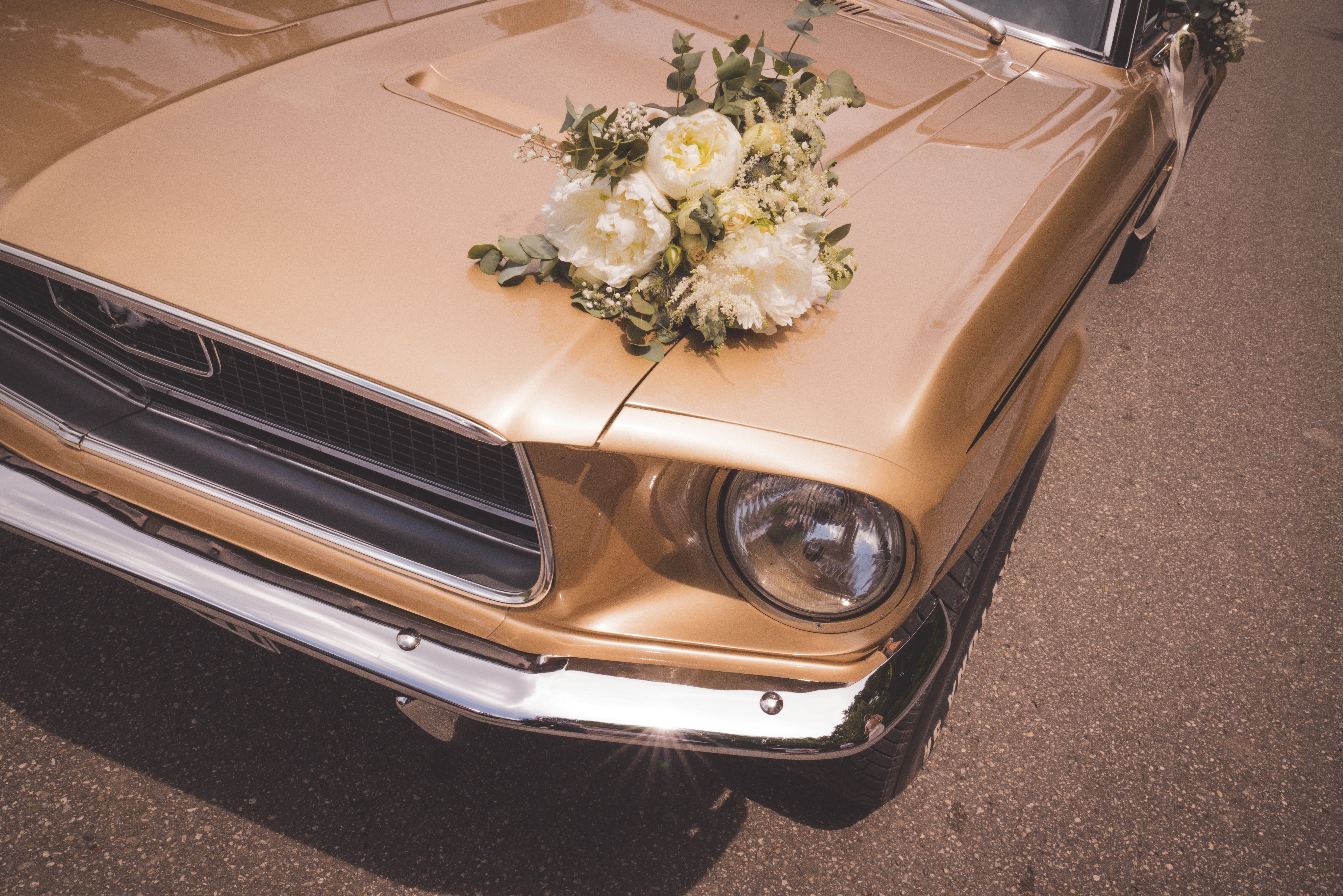 Classic gold car adorned with floral arrangements, showcasing vintage charm and modern elegance.