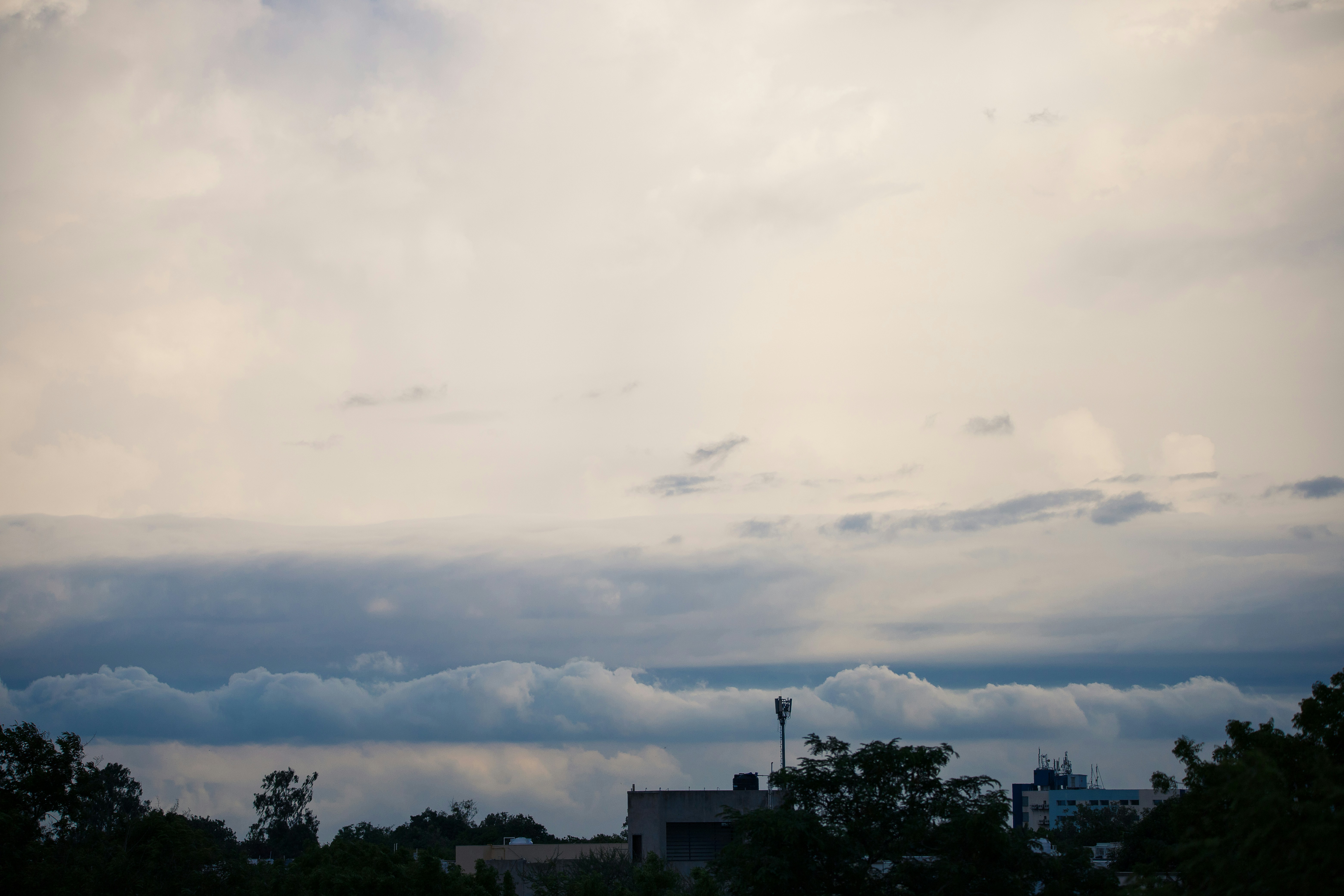 Clouds gathering ominously over a cityscape, hinting at an impending rainstorm.