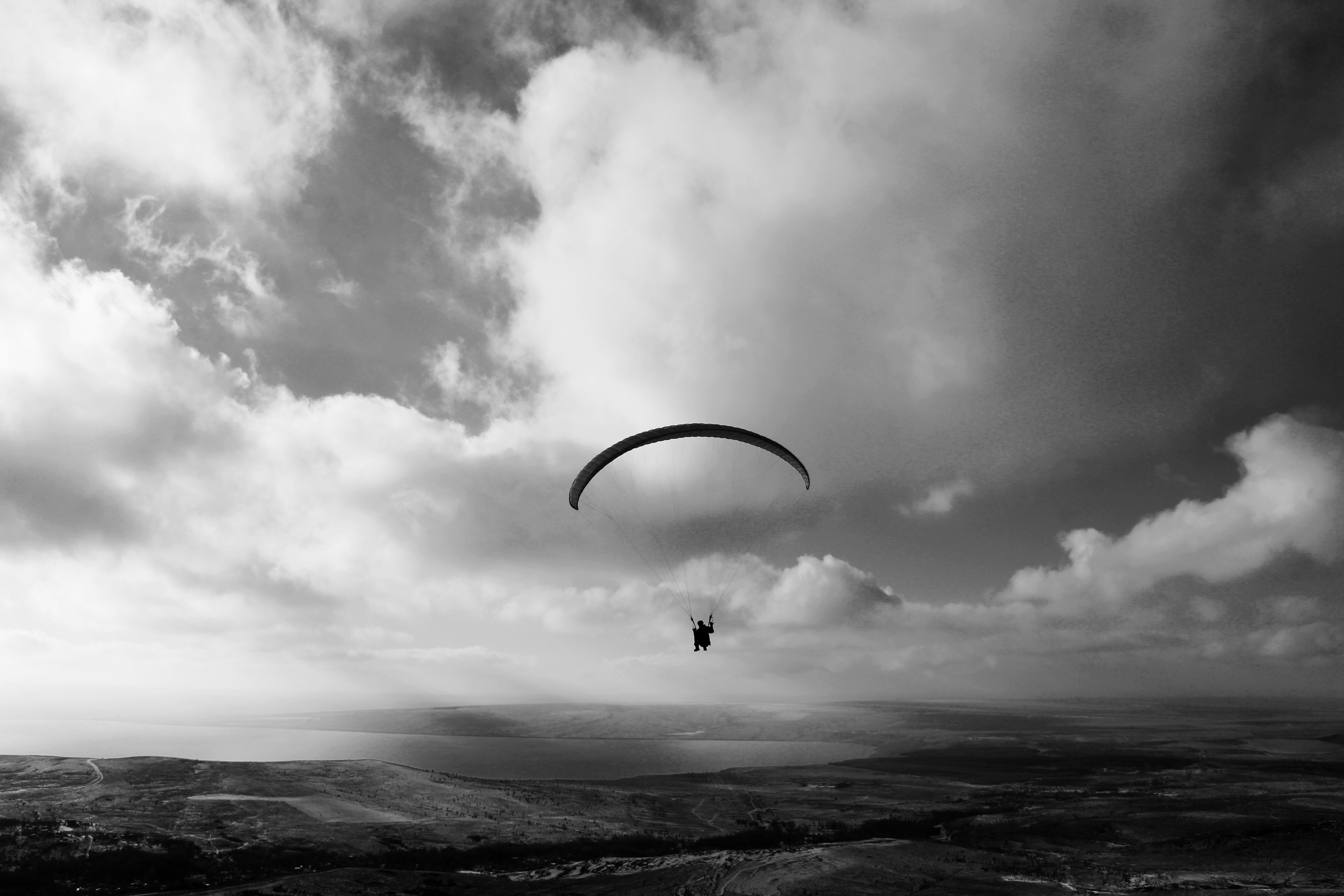 Midair Silhouette: Paraglider against a Vast, Clouded Horizon
