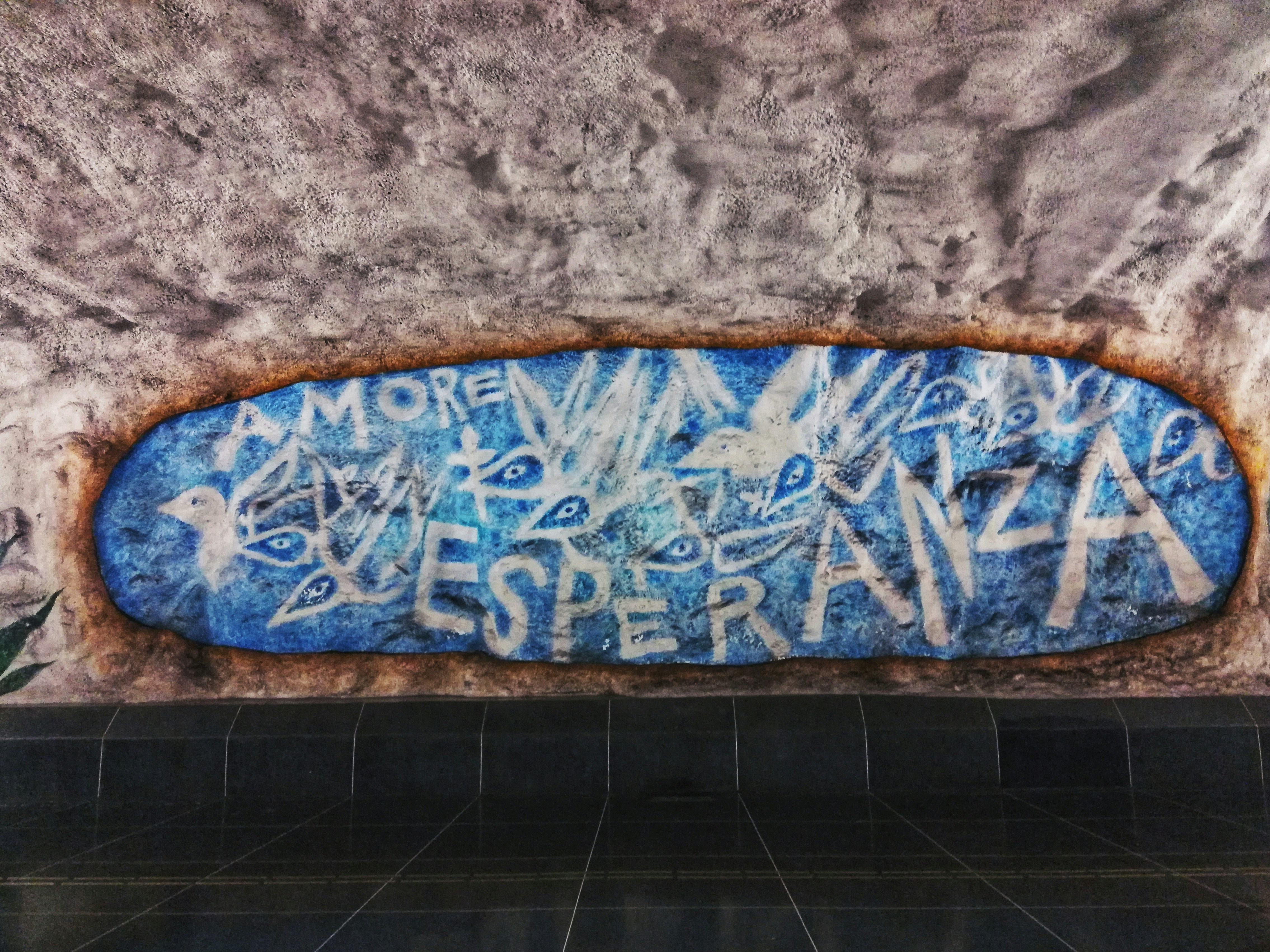 Vibrant mural featuring the words 'amor' and 'esperanza' surrounded by stylized birds, conveying a message of love and hope in a public space.