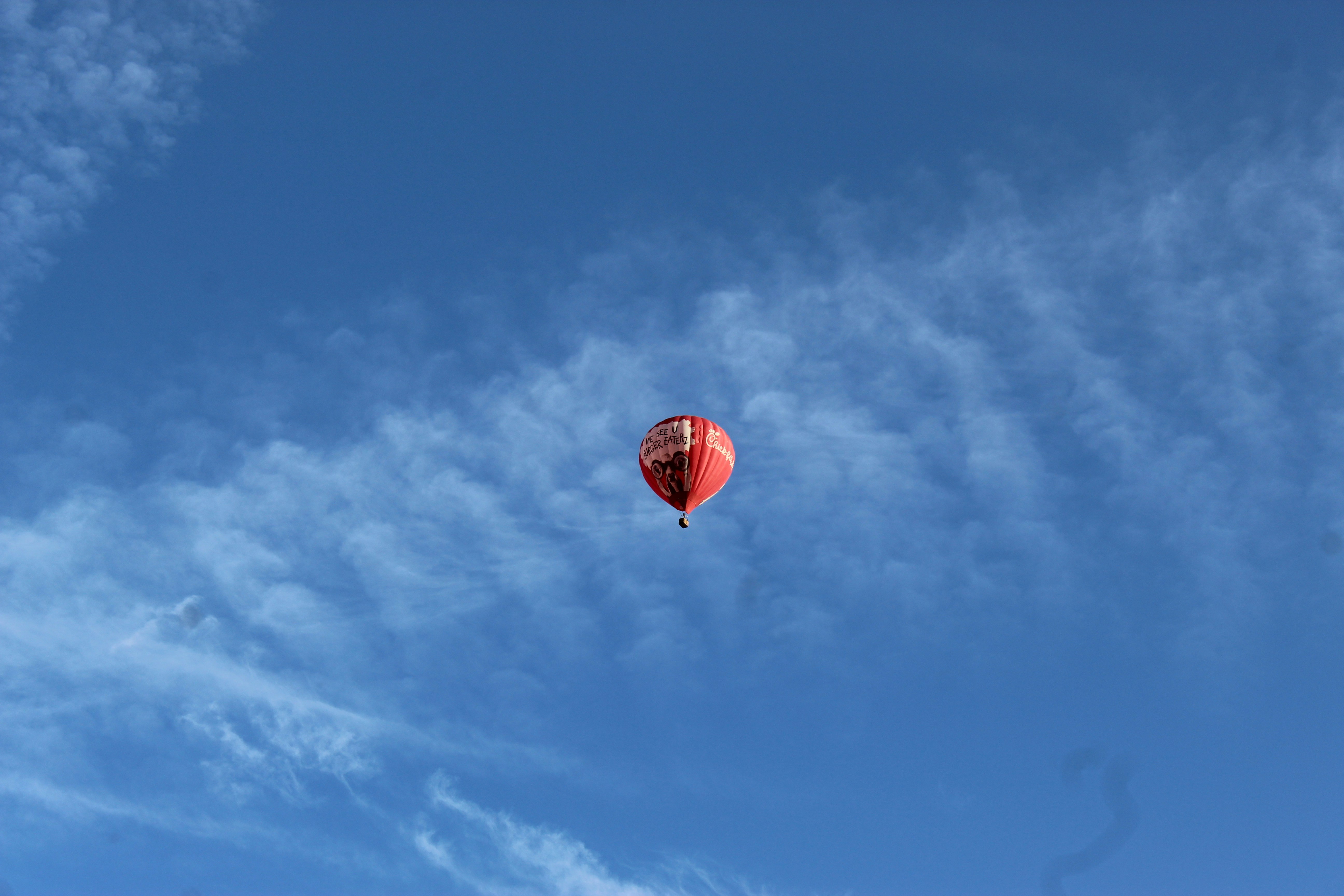 Foto Balon udara panas merah di udara di bawah langit biru pada siang ...