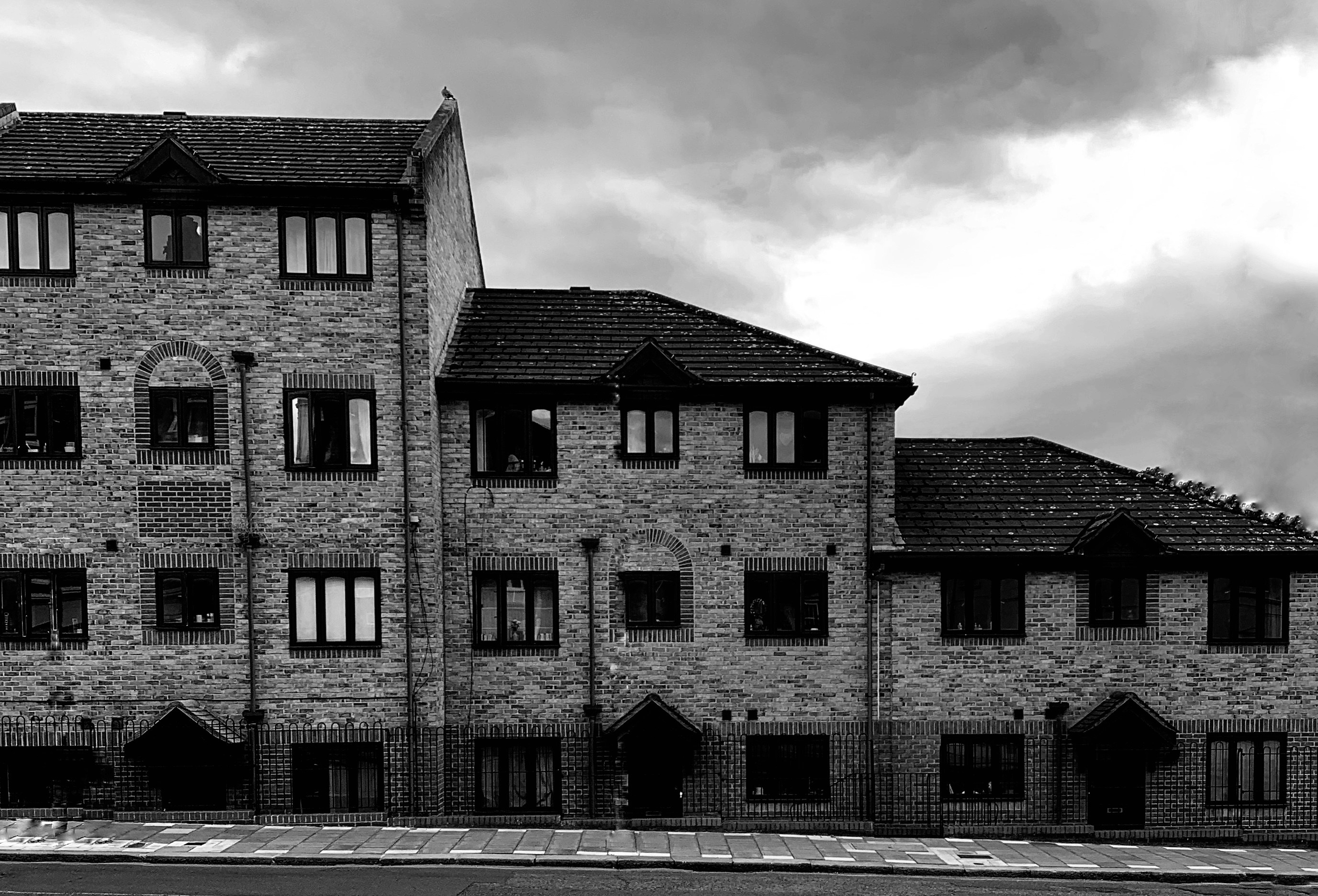 Brick apartment building with a symmetrical facade under a moody sky, emphasizing geometric patterns and textures.