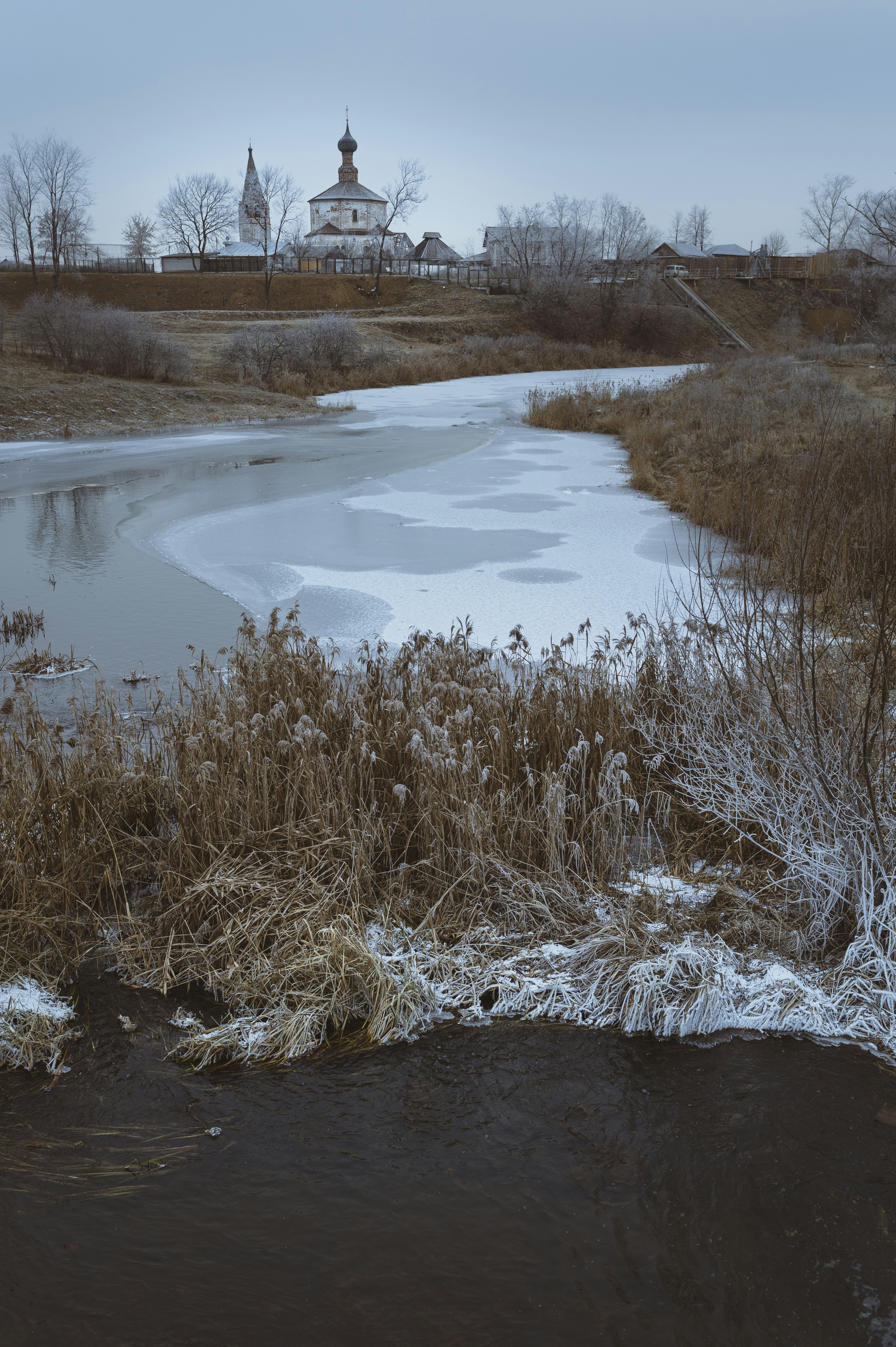 Icy Bend Toward a Weathered Church: Winter Light Over the Frosted River