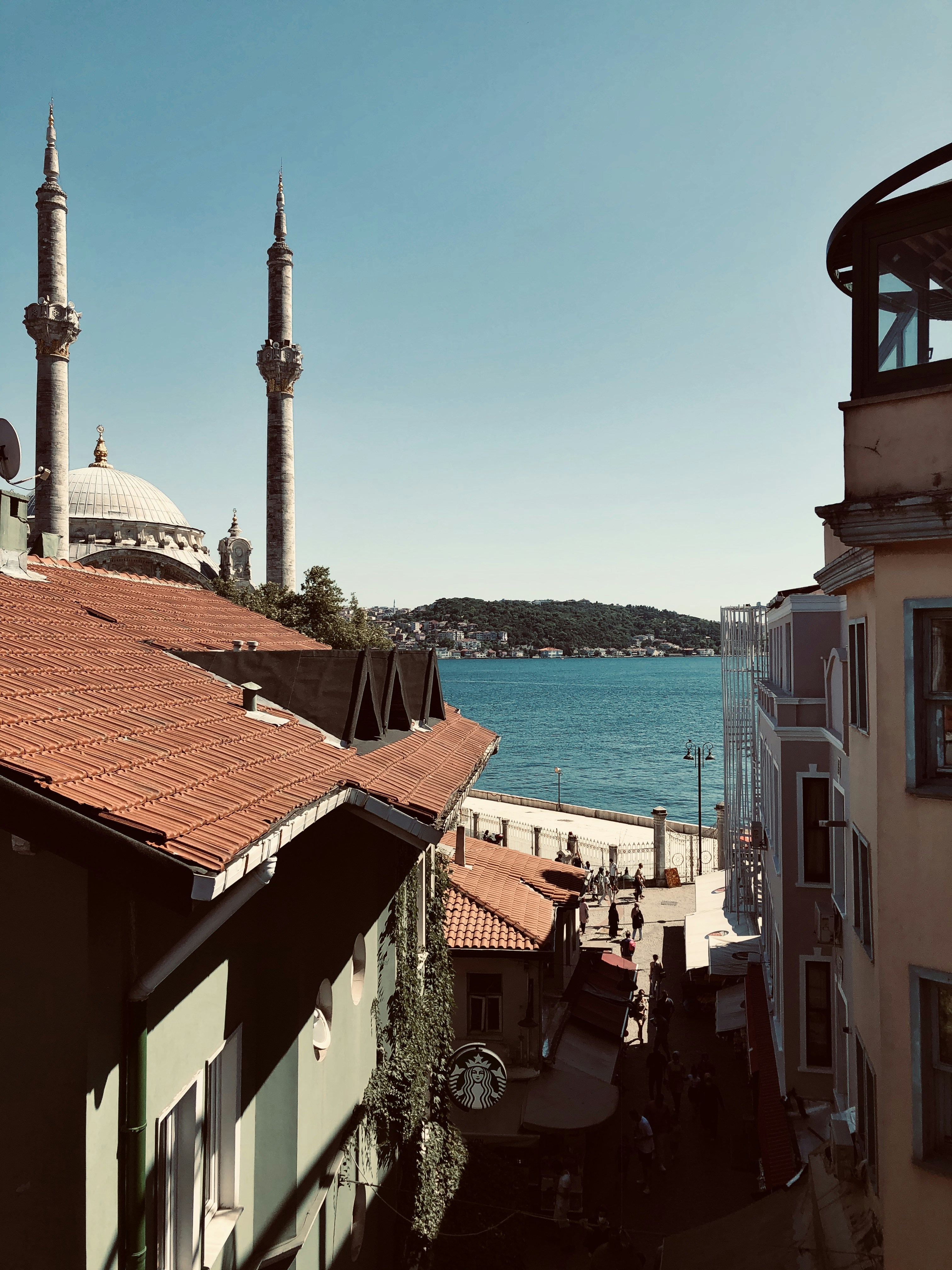 Historic architecture frames a serene waterfront view with minarets rising above the skyline. The scene captures the blend of urban life and natural beauty.