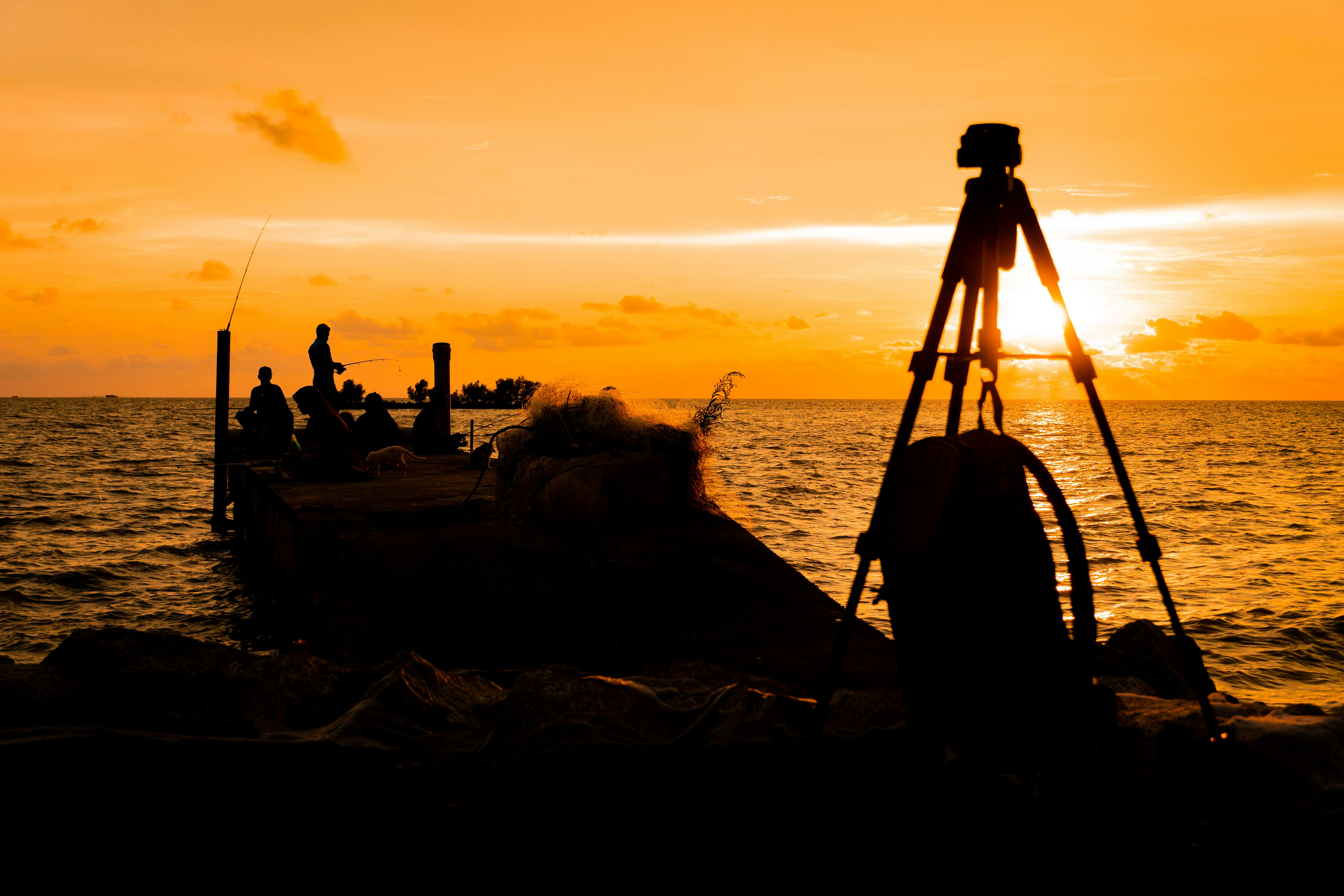 Silhouette on the Dusk Pier: A Tripod, a Boat, and the Golden Horizon