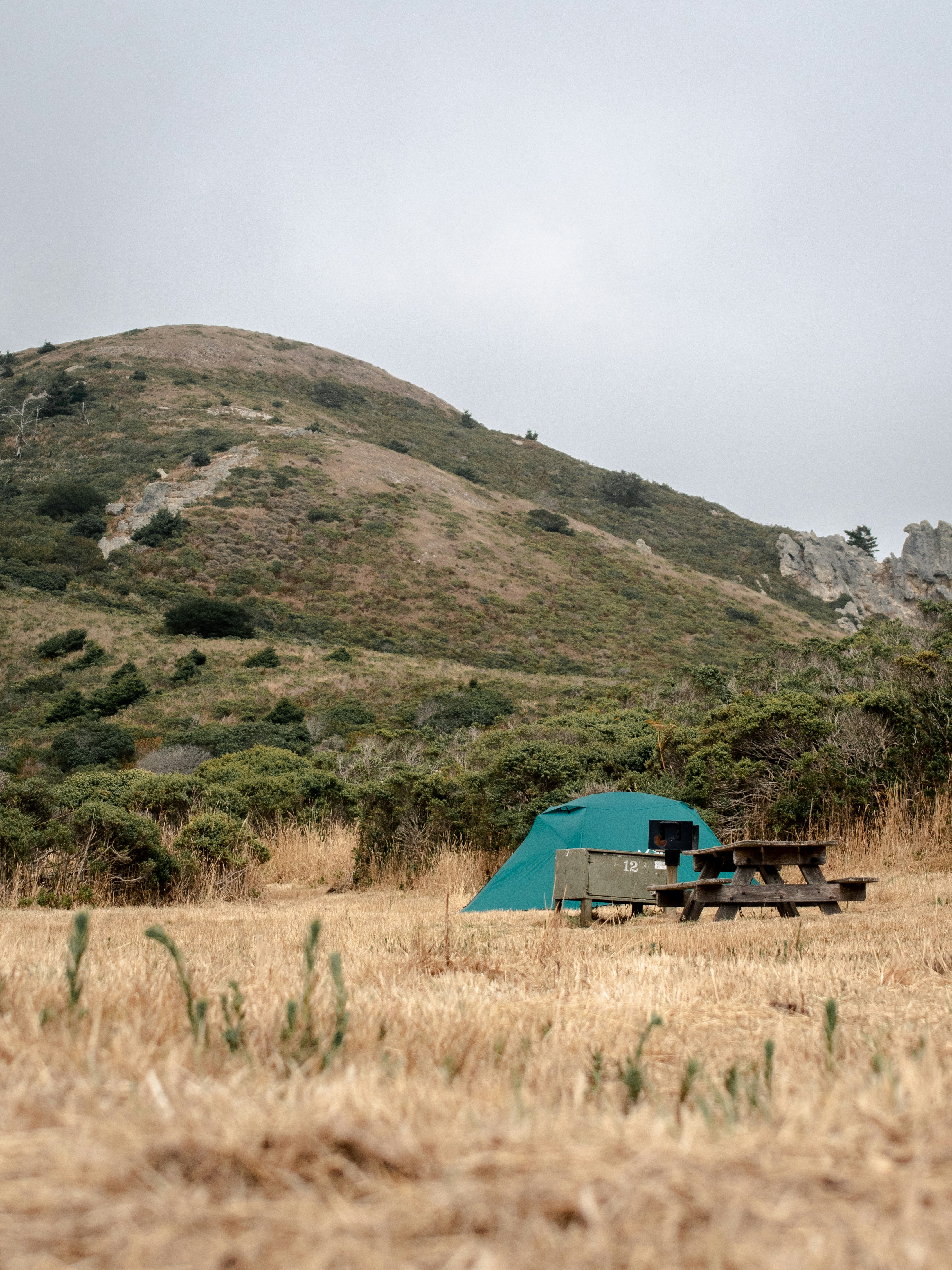 blue and green tent on green grass field near mountain during daytime