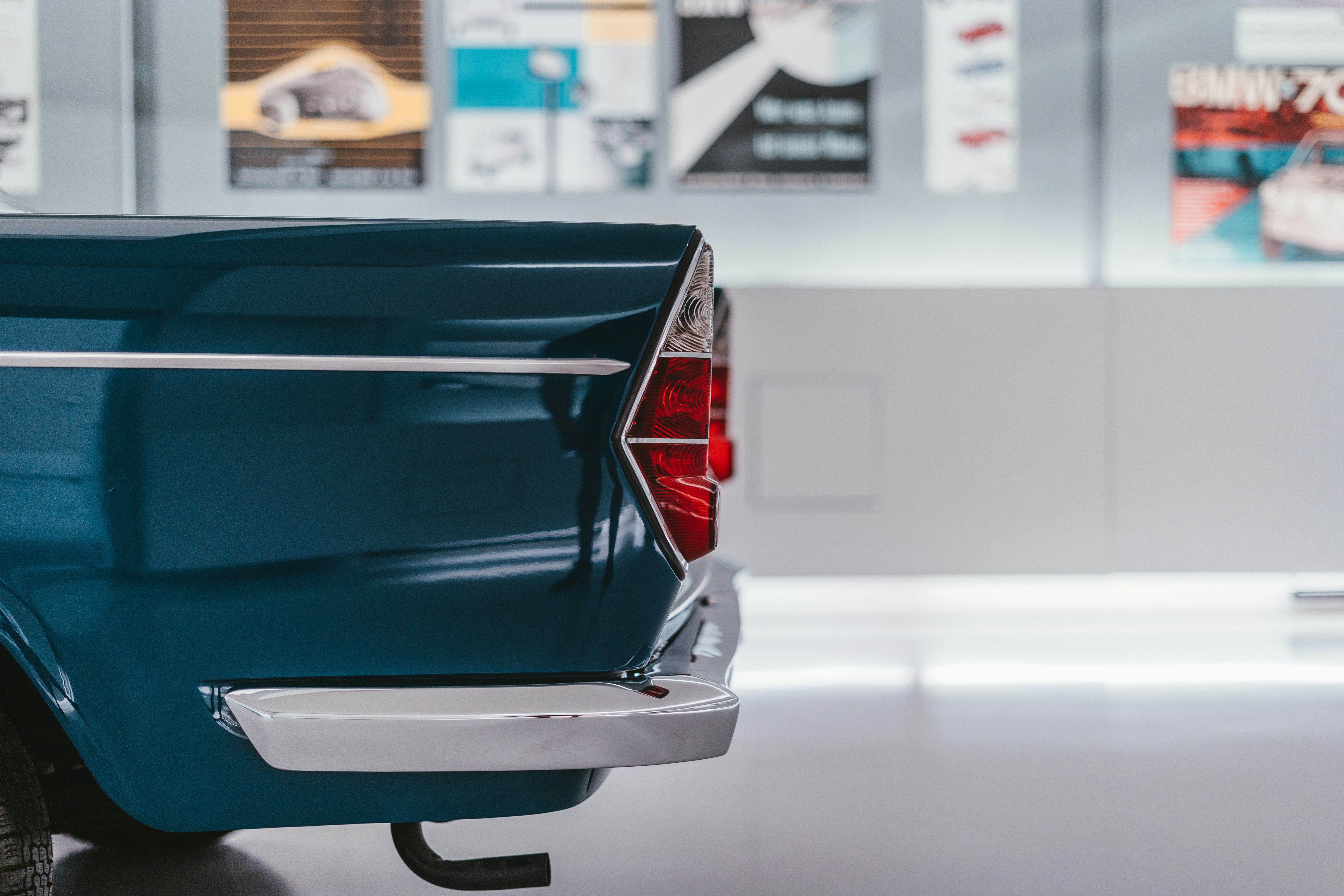 Teal Vintage Sedan Tail-Light Portrait in a Minimal Showroom