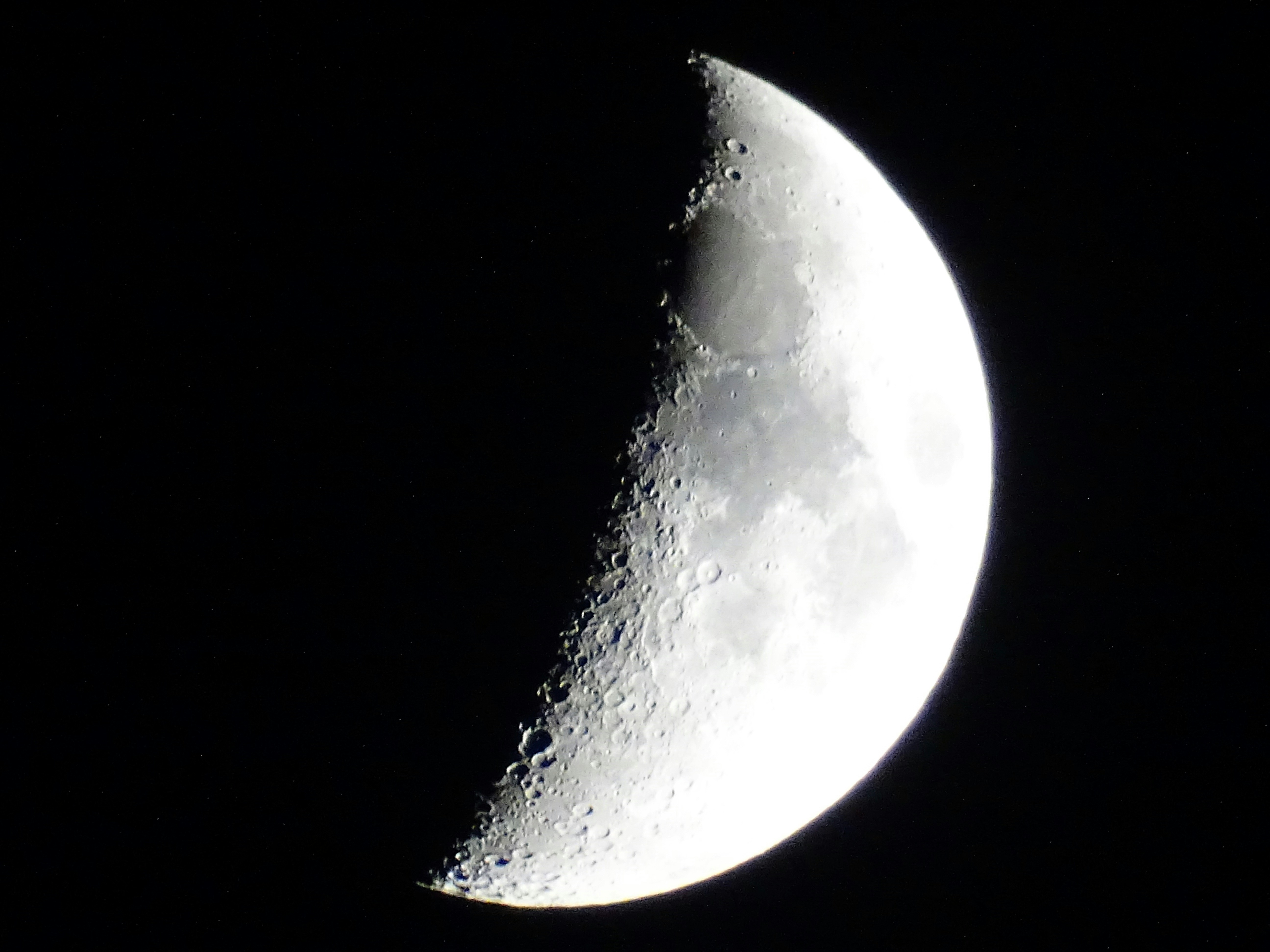 Crescent moon illuminated against a deep black sky, showcasing intricate surface details and craters.