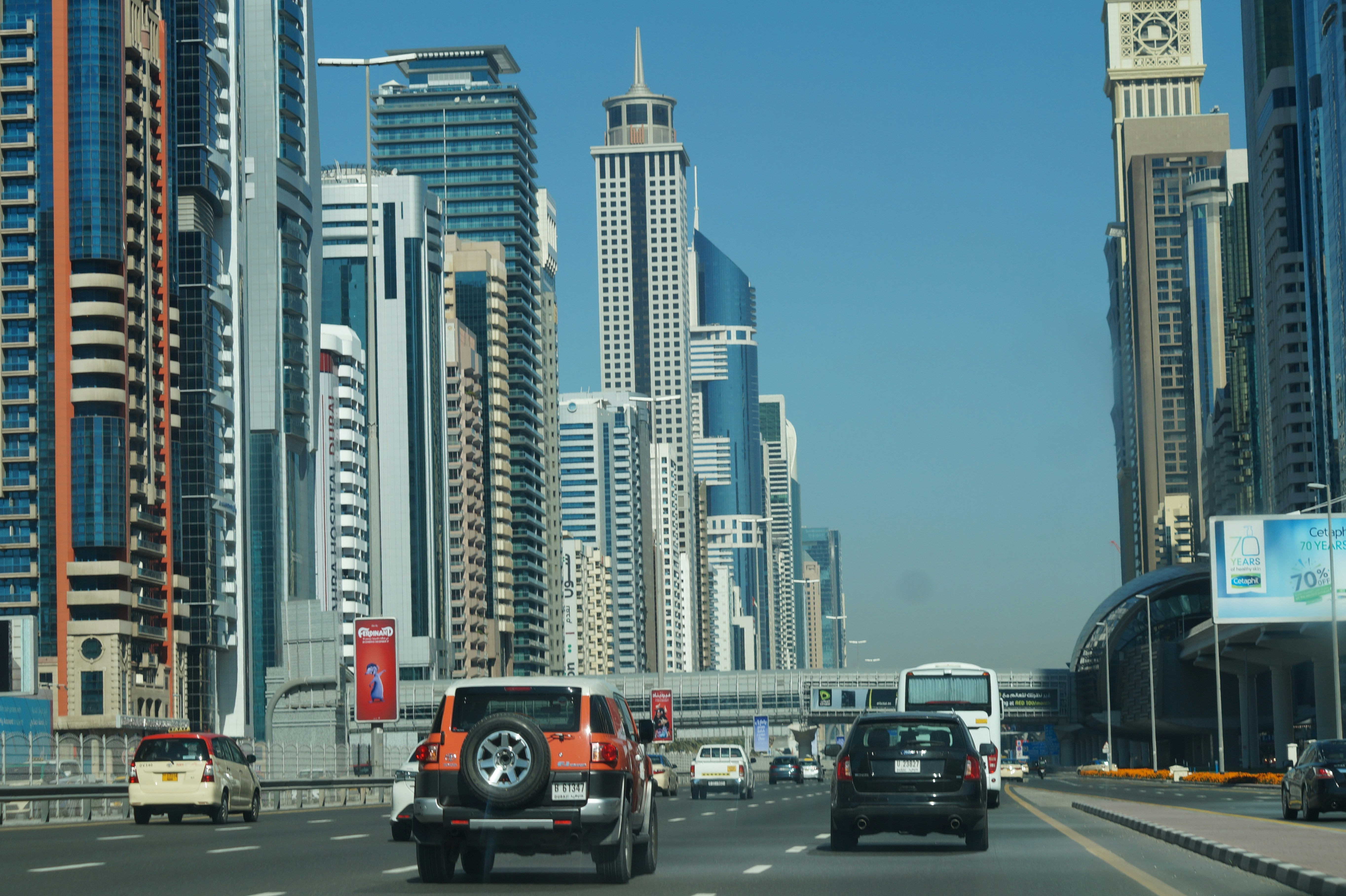 Dynamic cityscape featuring a bustling highway flanked by towering skyscrapers, showcasing modern architecture and urban life.