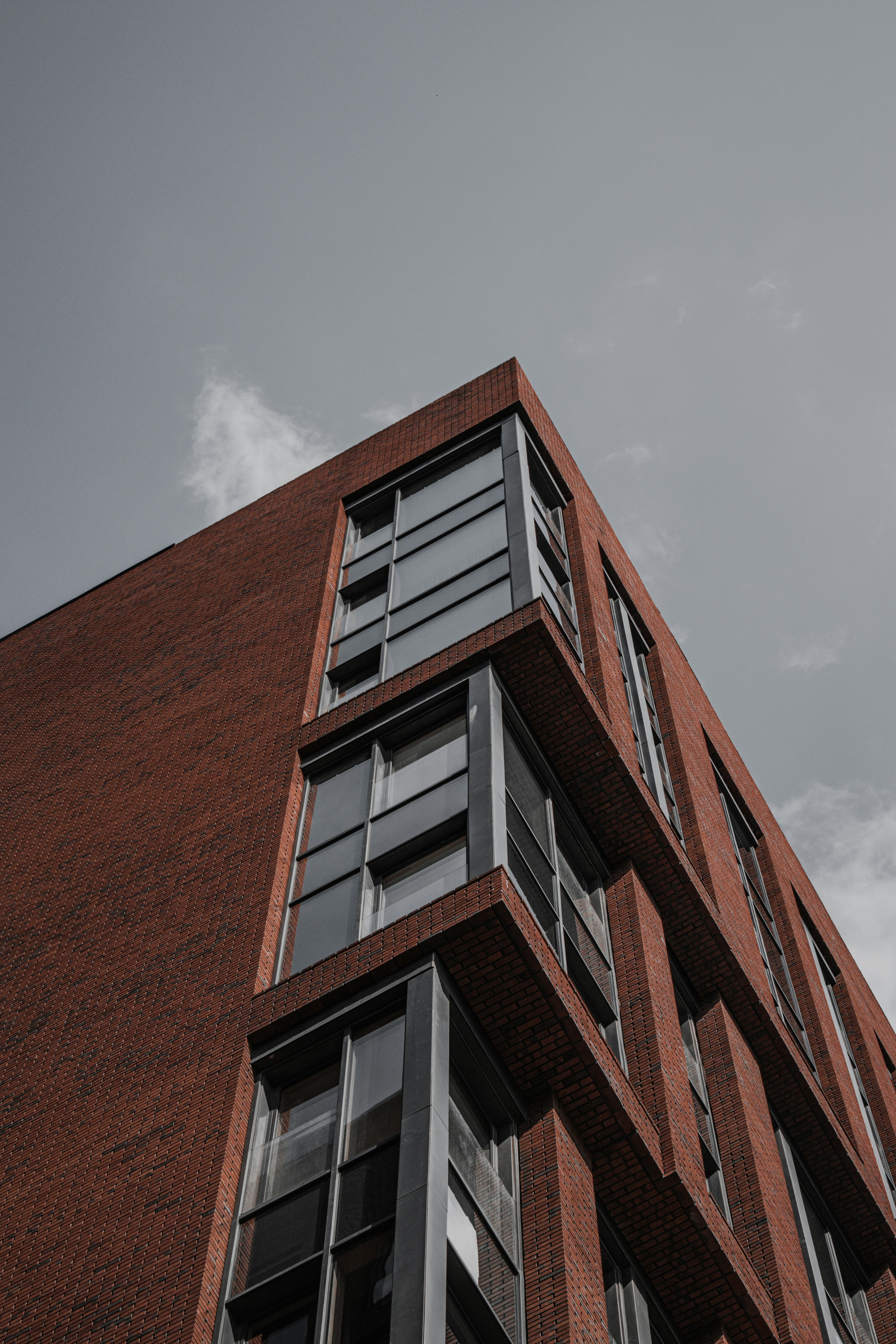 Contemporary brick building with large glass windows, captured from a low angle against a cloudy sky.
