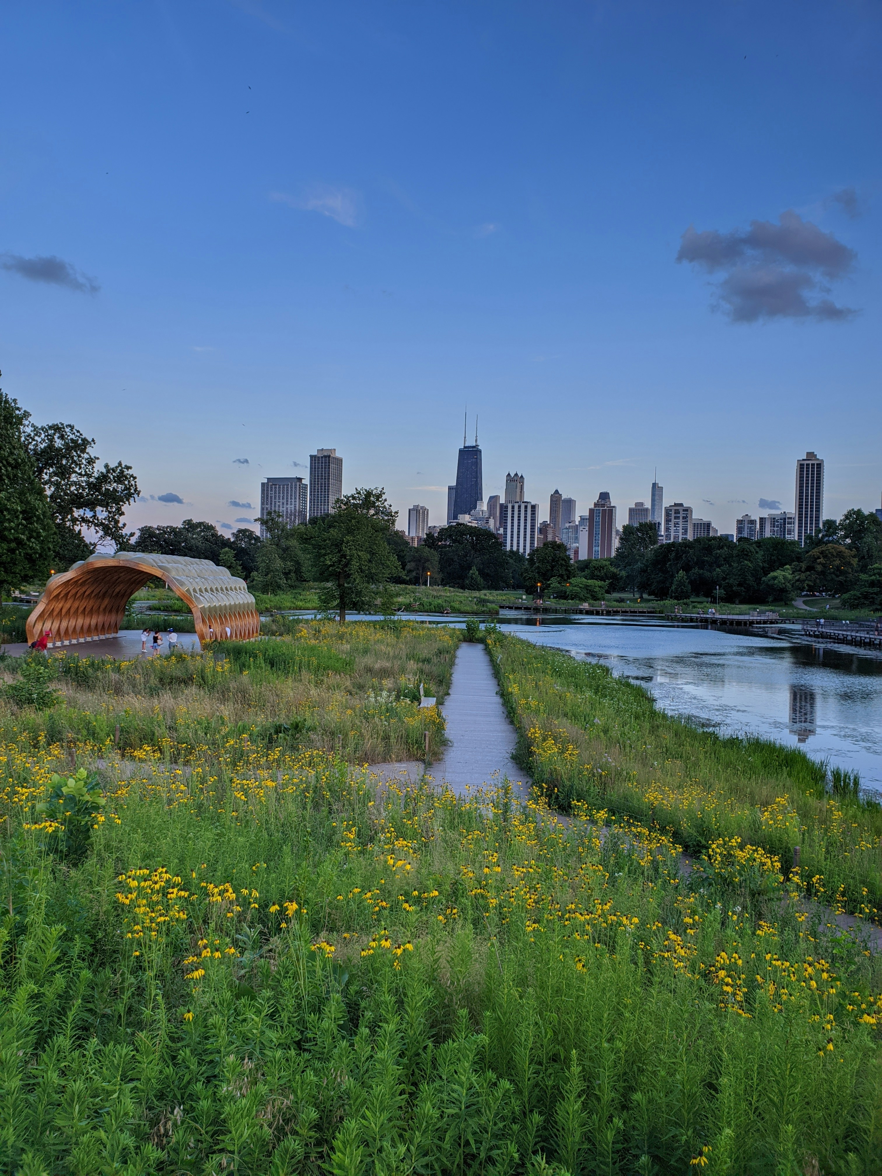 Curved Pavilion Over a Wildflower Meadow Framing the City Horizon