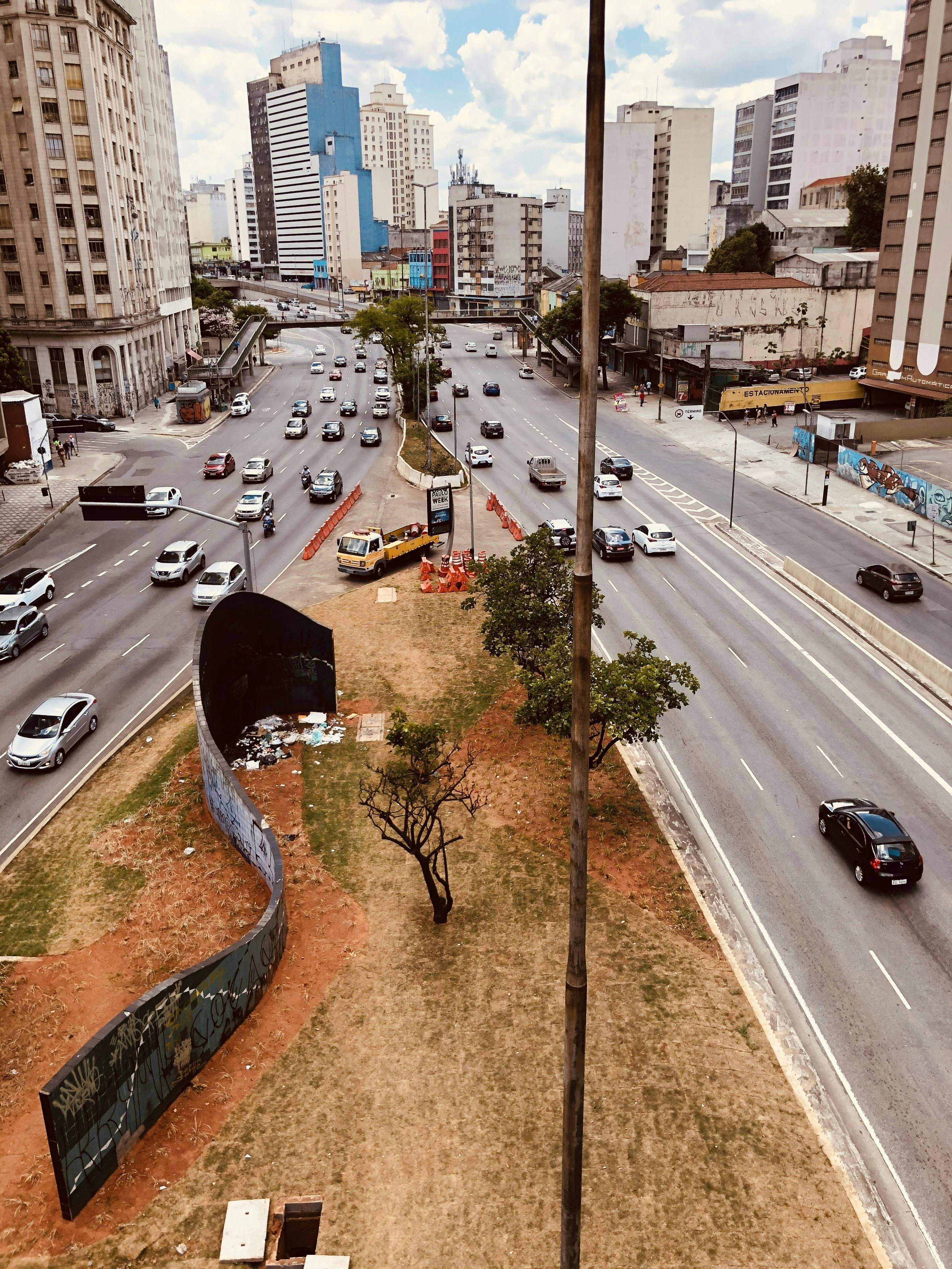 Busy urban intersection showcasing vehicles navigating through a bustling cityscape, framed by modern buildings and greenery.