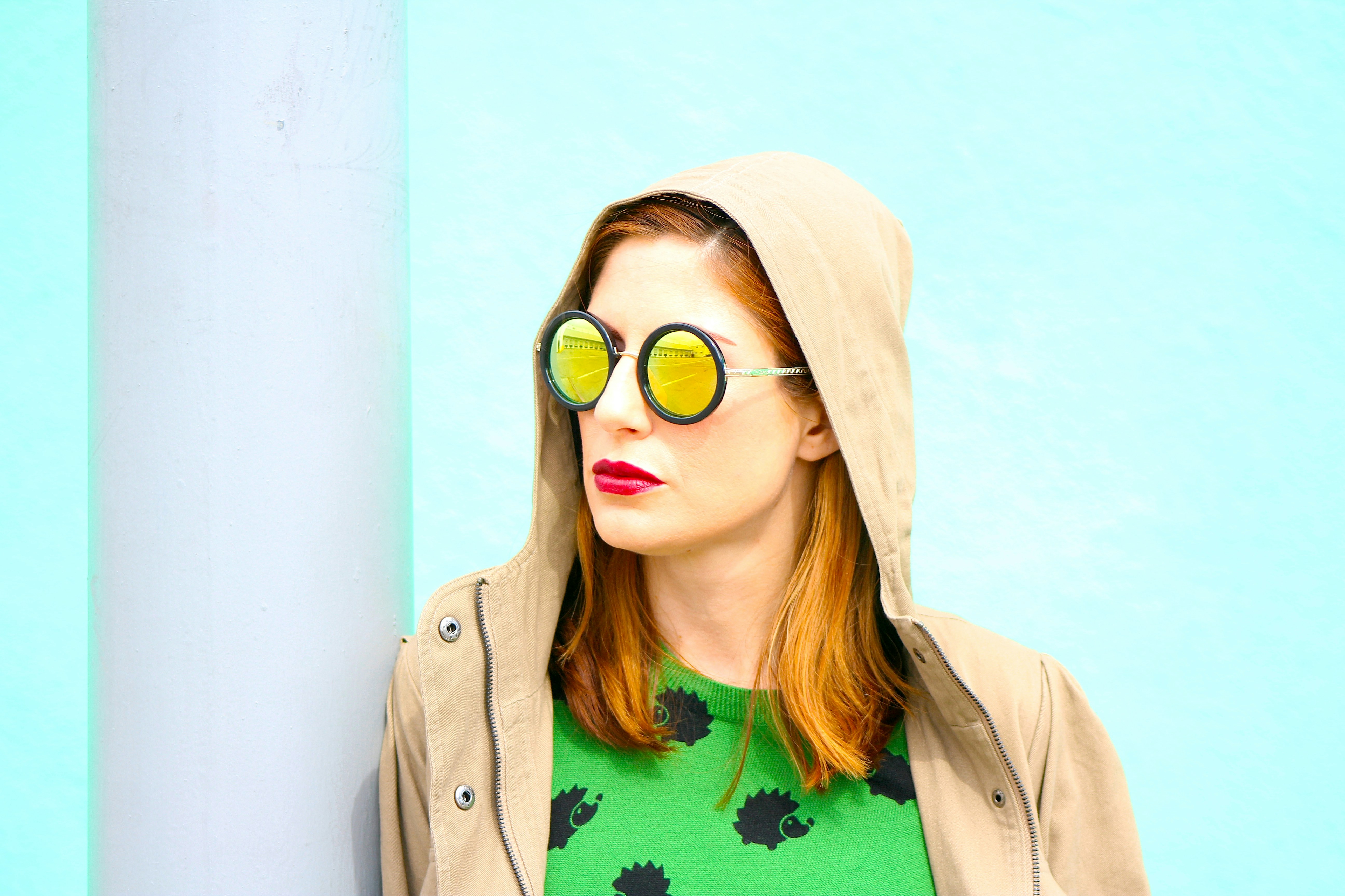 Hooded Elegance Against Turquoise: A Portrait with Yellow-Lensed Gaze