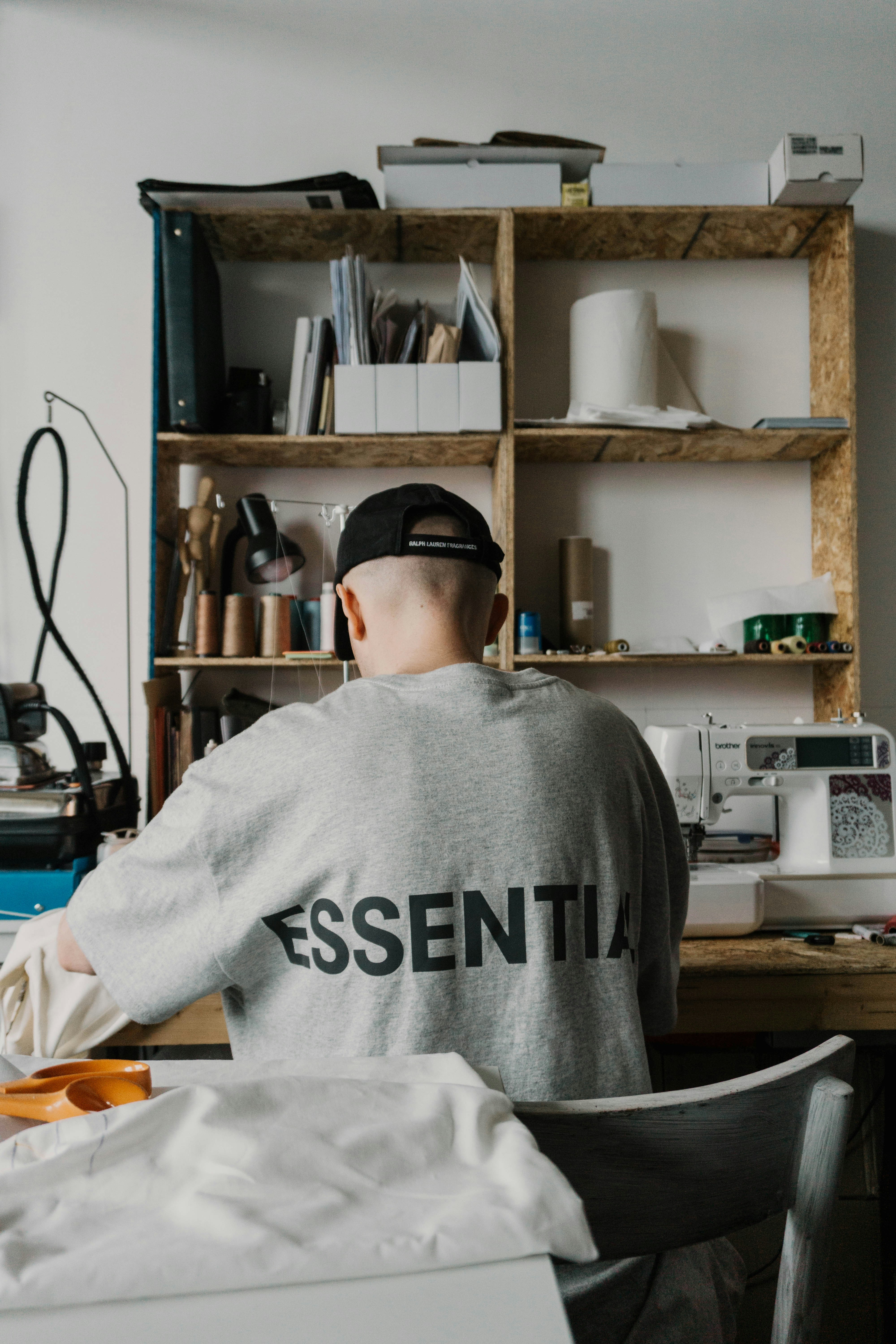 Individual focused on sewing in a creative workspace, surrounded by tools and materials. The scene captures the essence of craftsmanship.