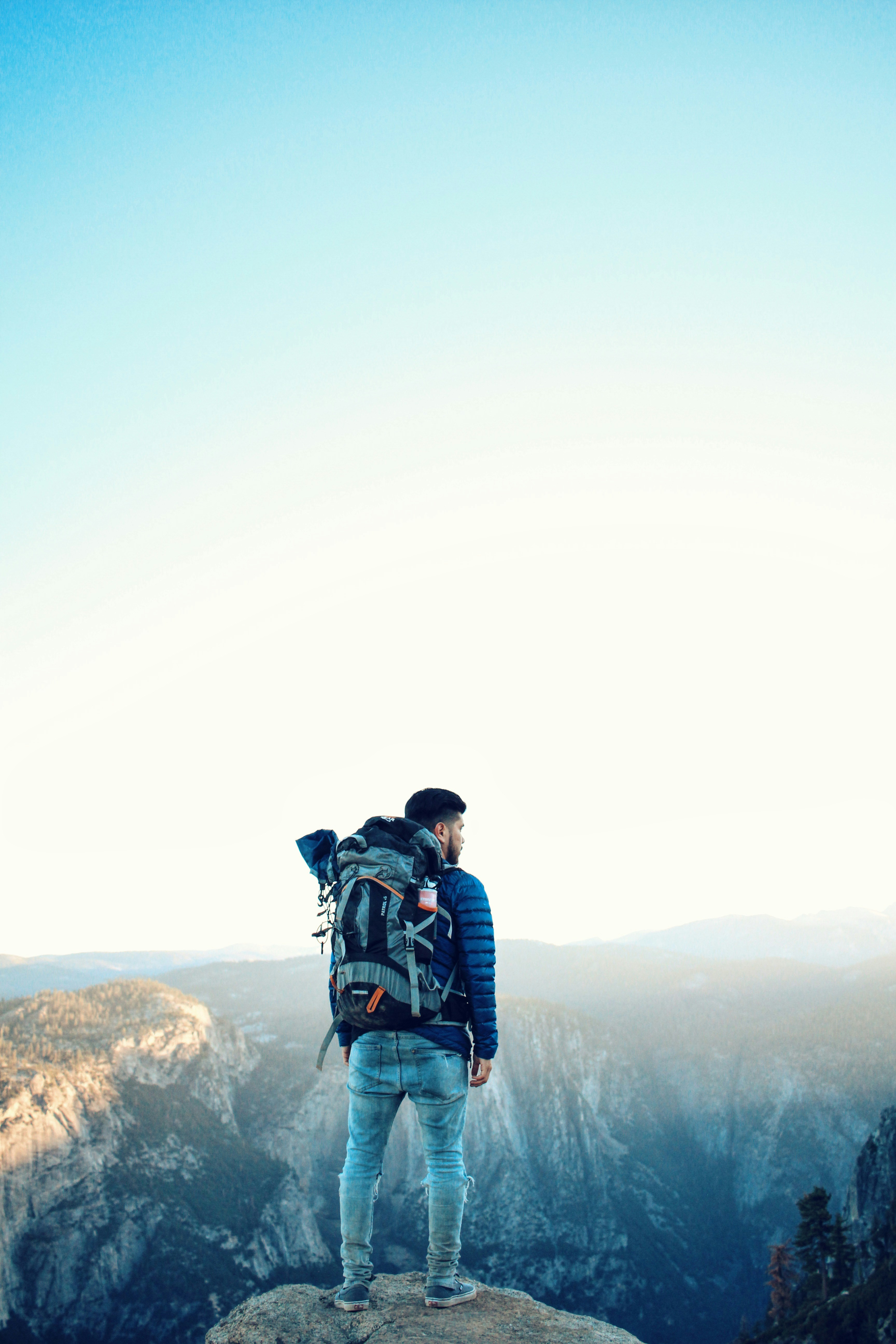 Man in black and red jacket carrying black backpack standing on brown ...