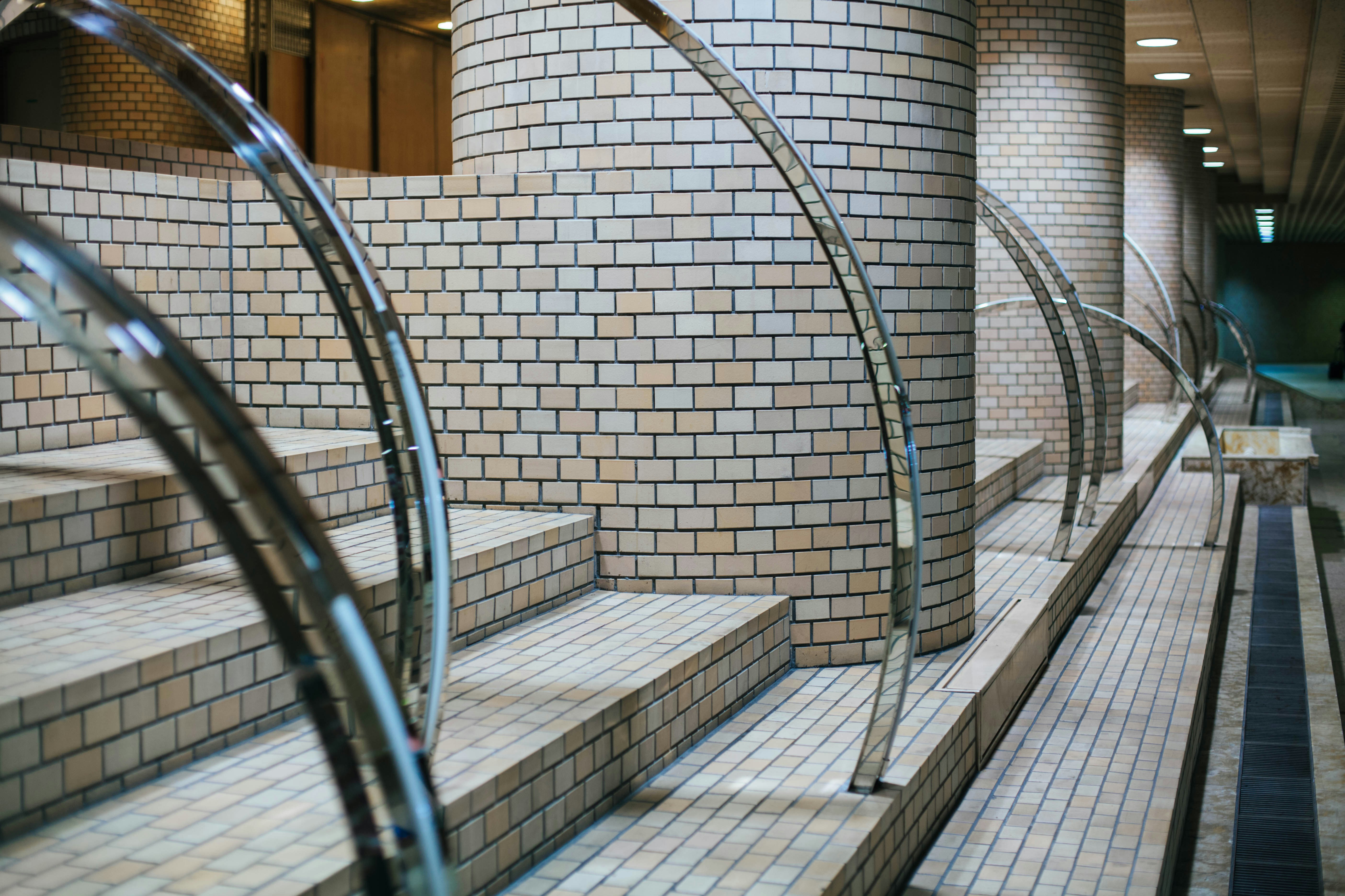 Vanishing Arcade: Curved Handrails Converging Toward a Green-Lit Corridor