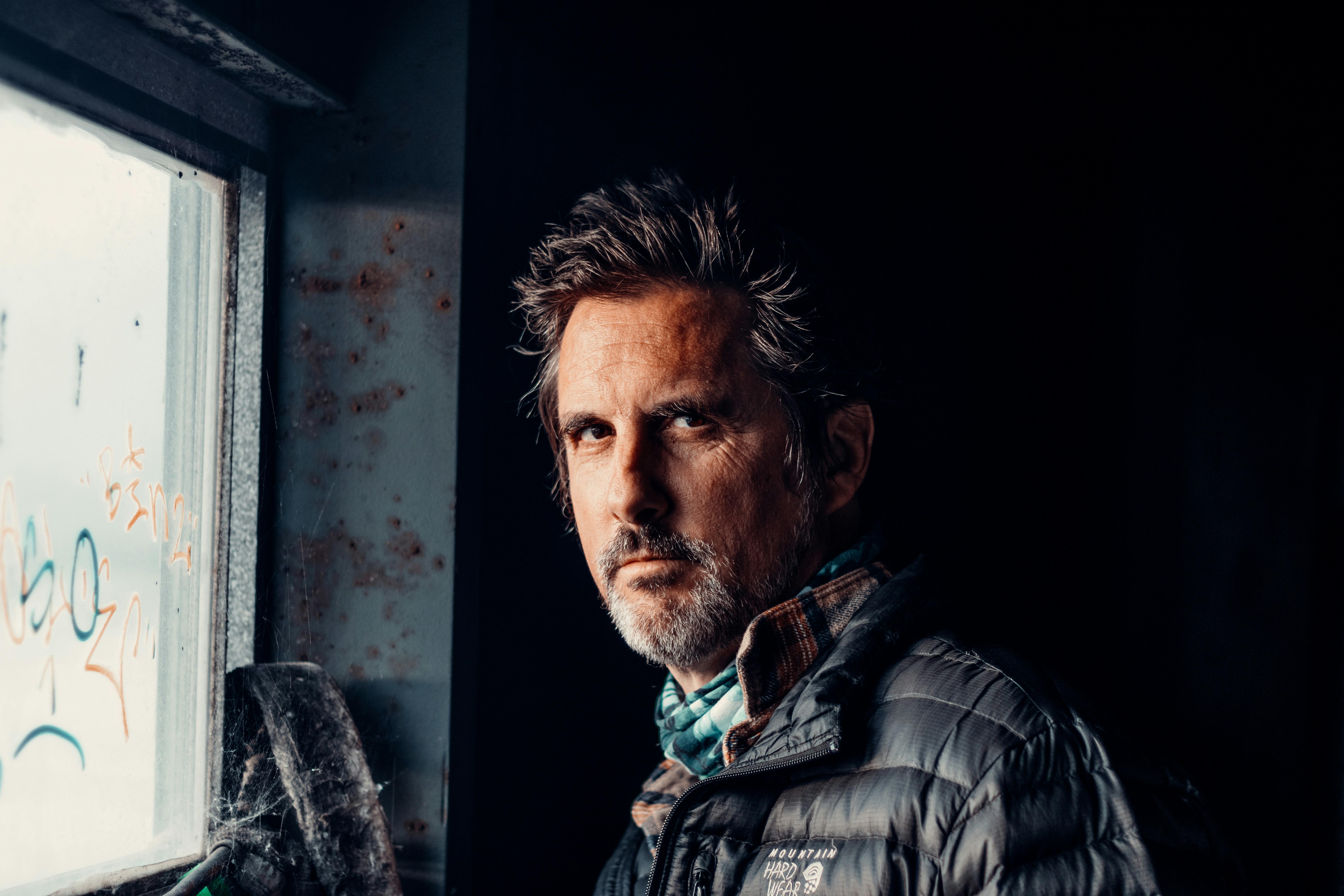 A man standing next to a window in a dark room photo – Free Portrait ...