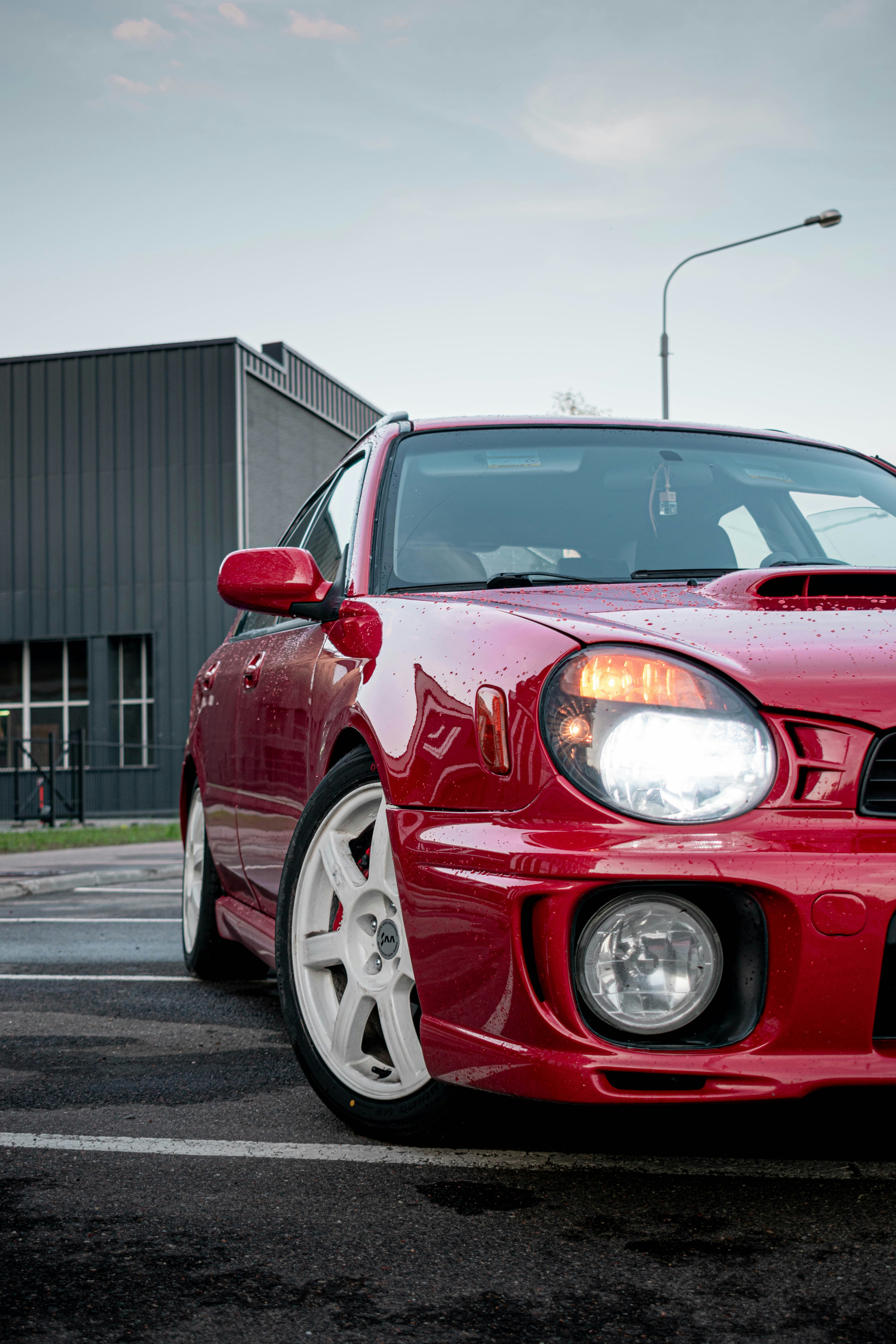 Crimson Front Quarter: A Tuned Hatchback in an Industrial Parking Lot